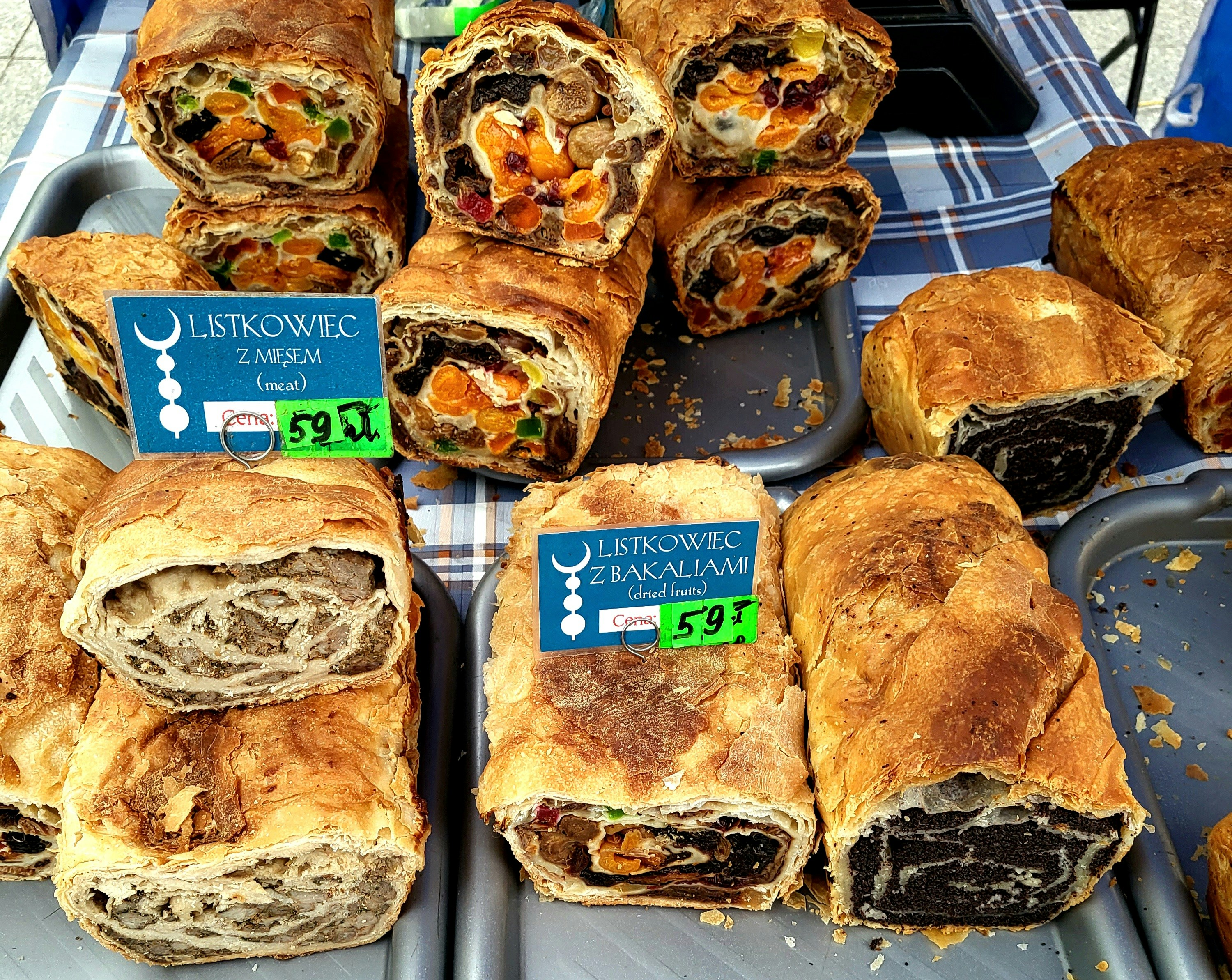 Assorted strudels with various fillings stacked on a market table.