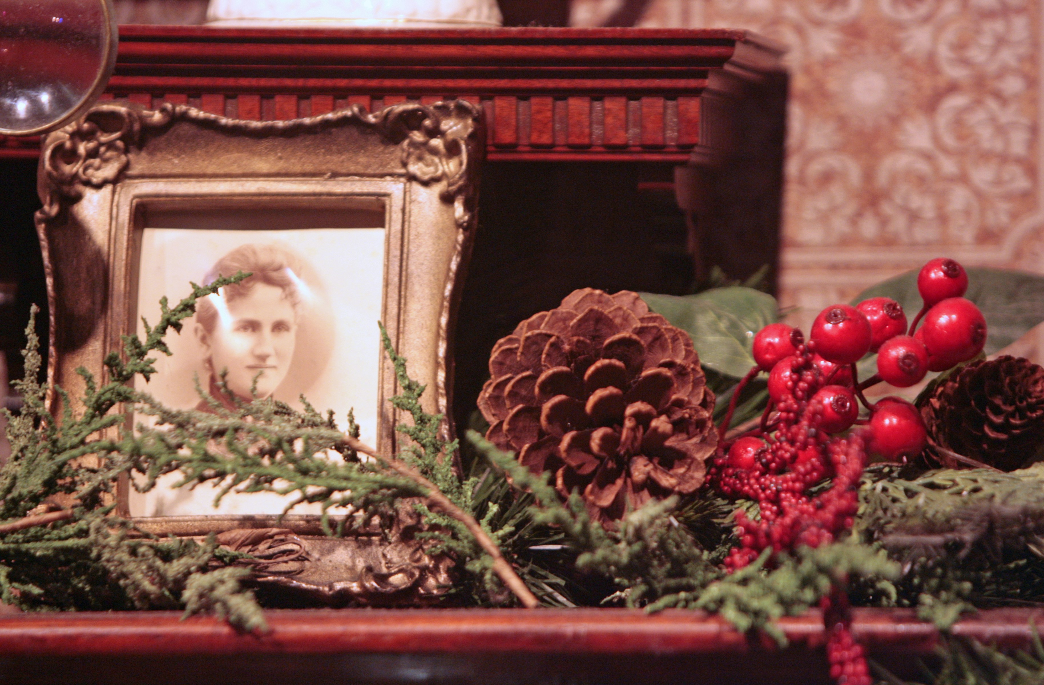 Portrait on the Mantel: Vintage Frame Nestled Among Pine, Pinecone, and Red Berries