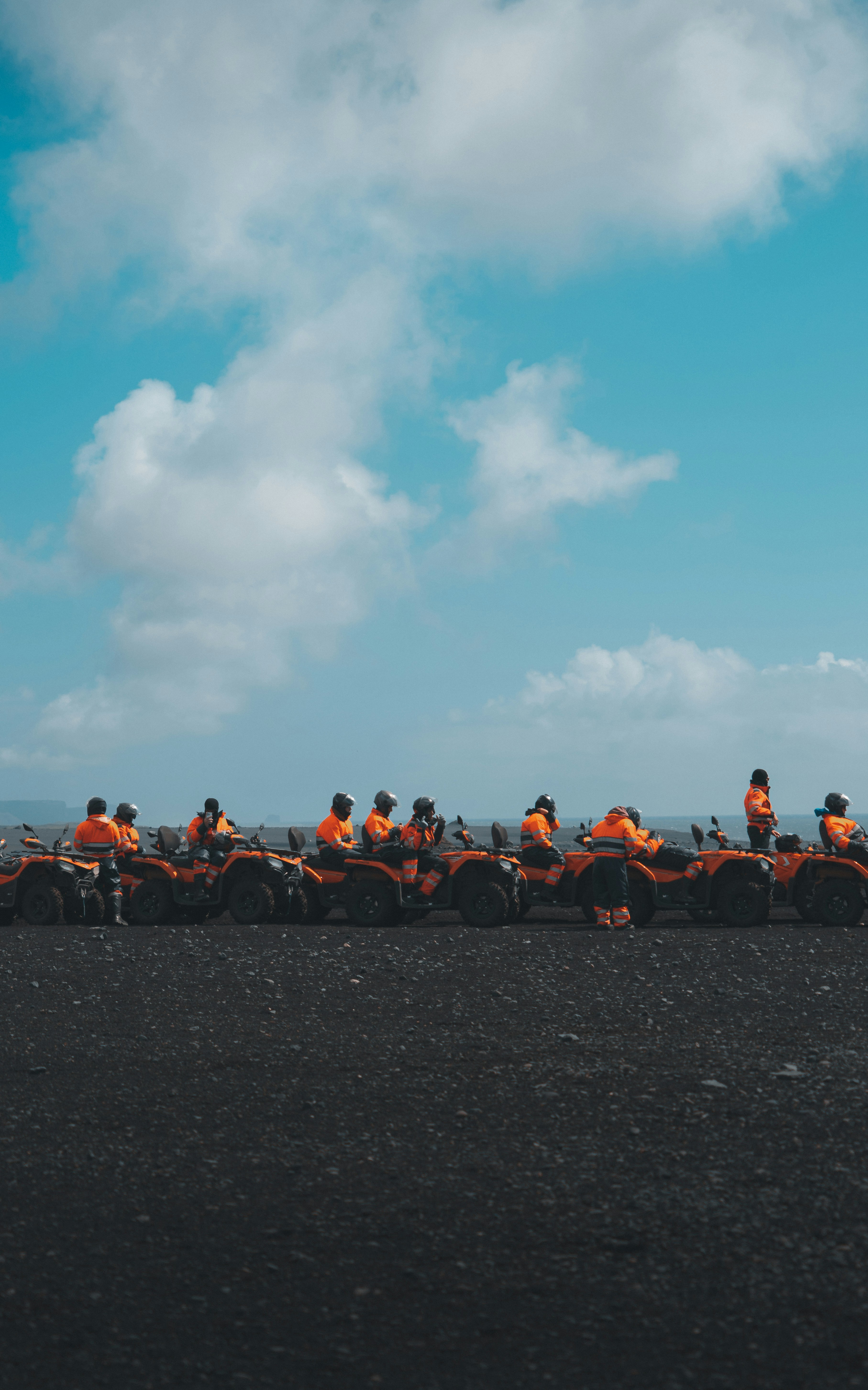 Orange-Clad Lineup on a Black Lava Beach Under a Vivid Sky