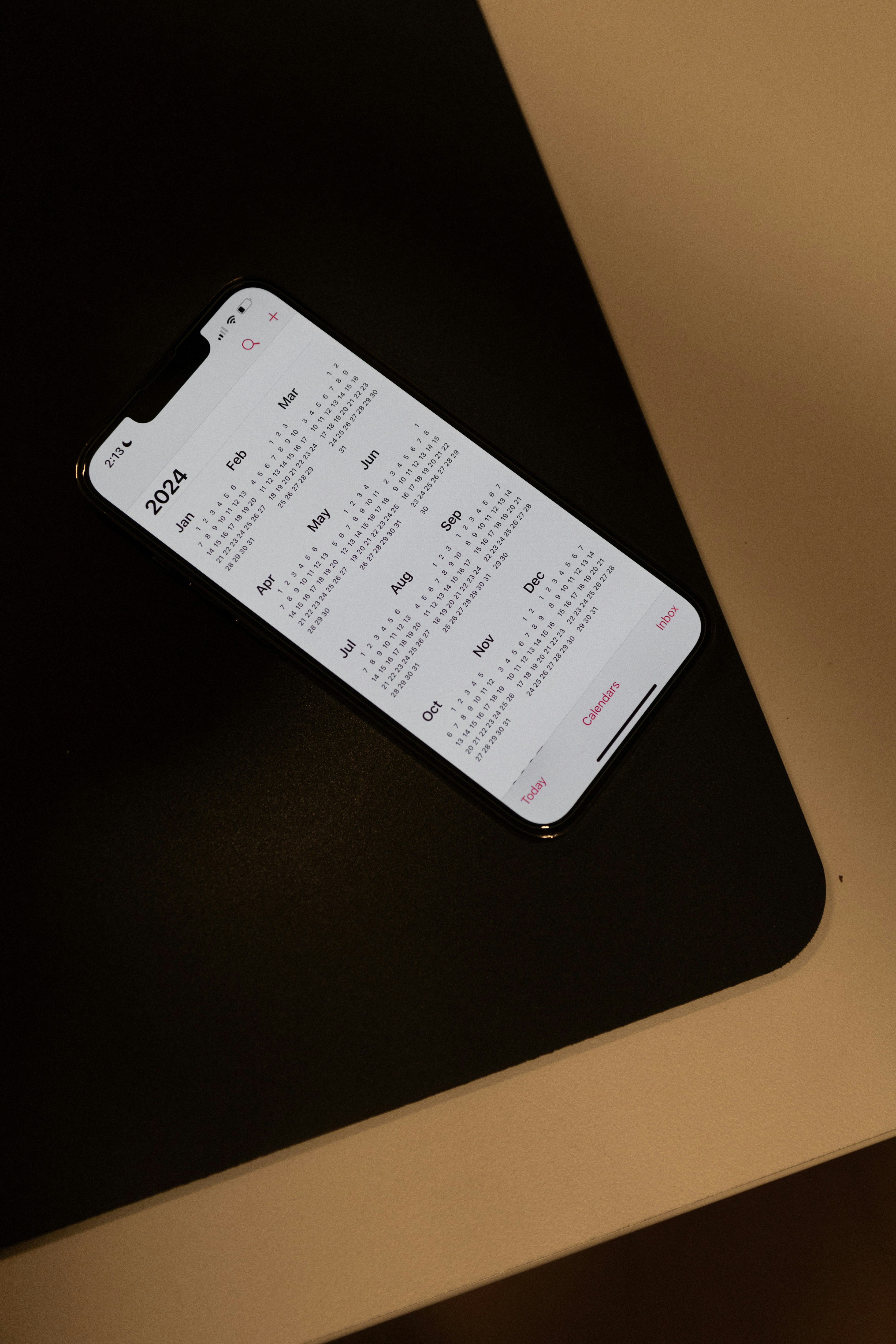 Smartphone displaying a calendar for the year 2024, resting on a sleek surface. The design emphasizes modern organization.