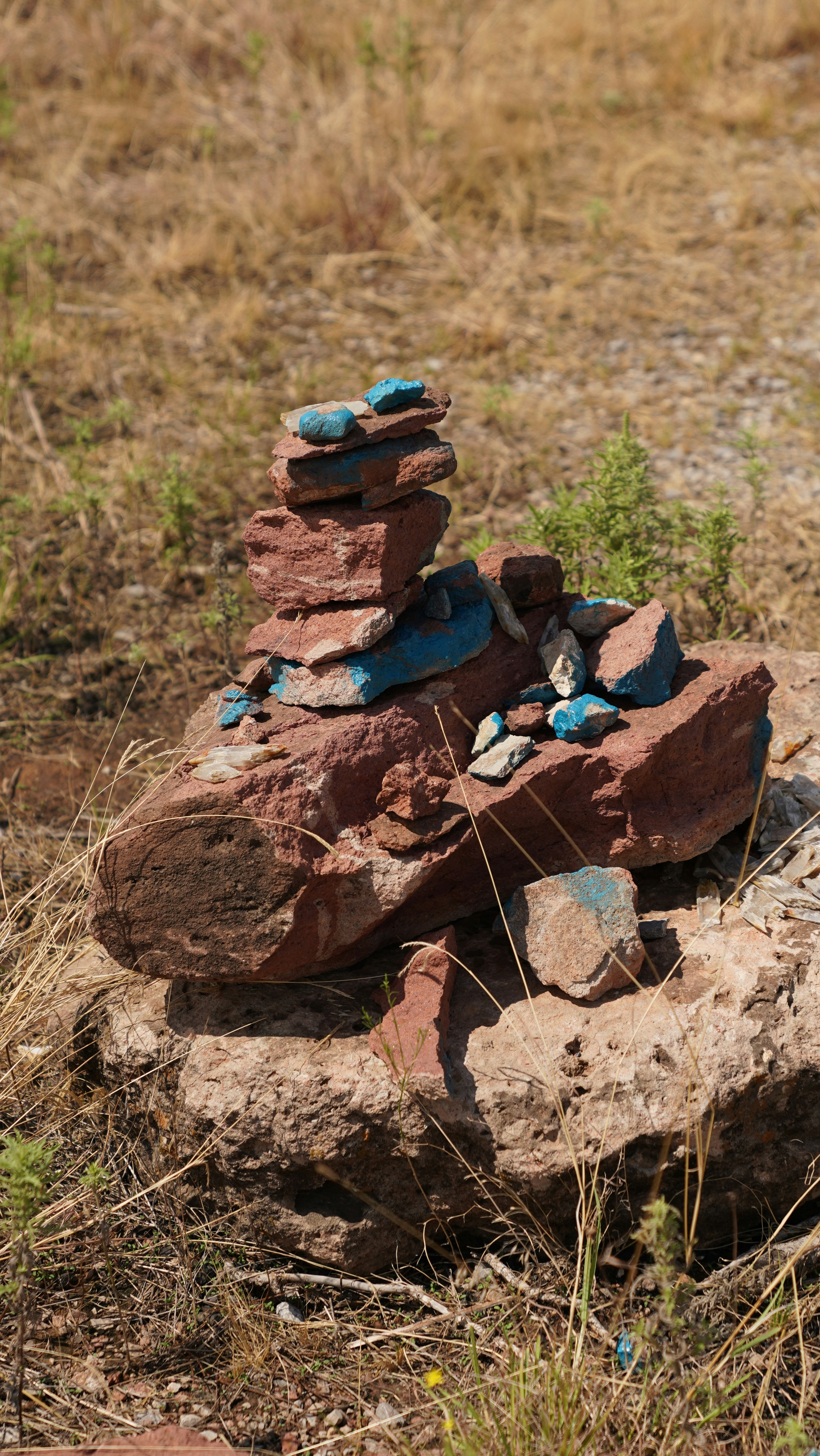 Stacked stones with blue paint in sunlit dry meadow