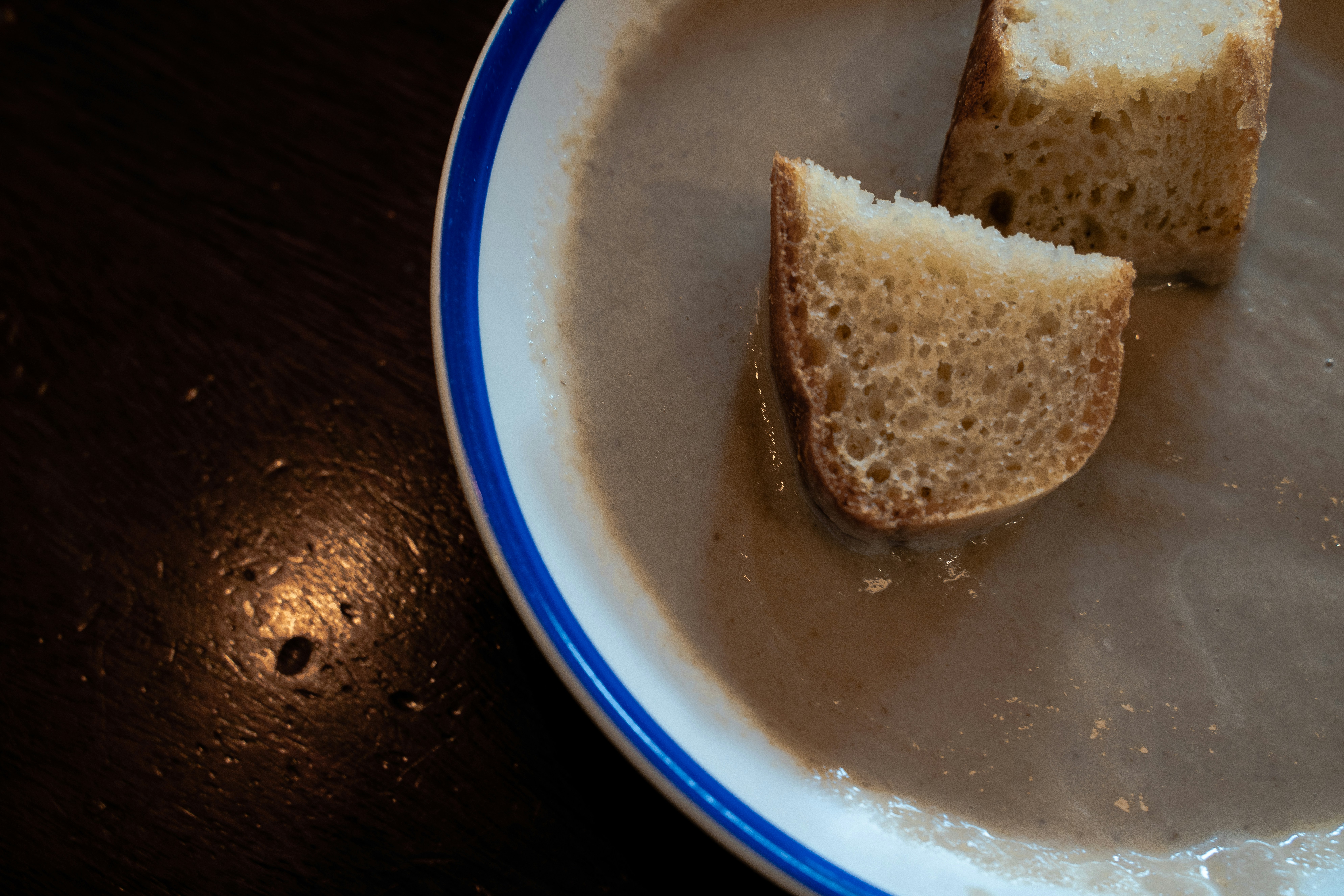 Crumbed Bread Dips into Creamy Soup on a Cerulean-Rim Plate