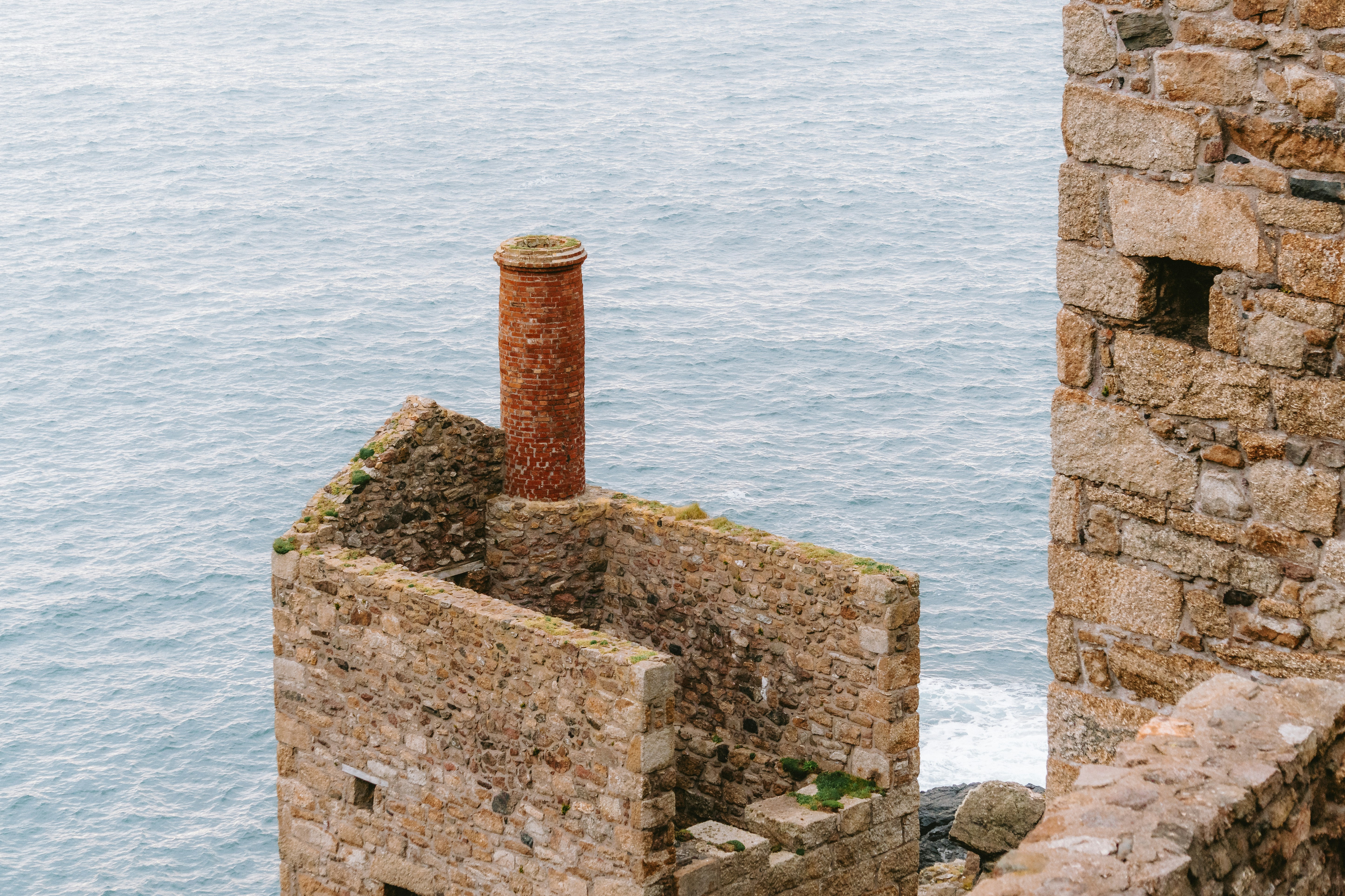 An old brick building sitting on top of a cliff next to the ocean photo ...