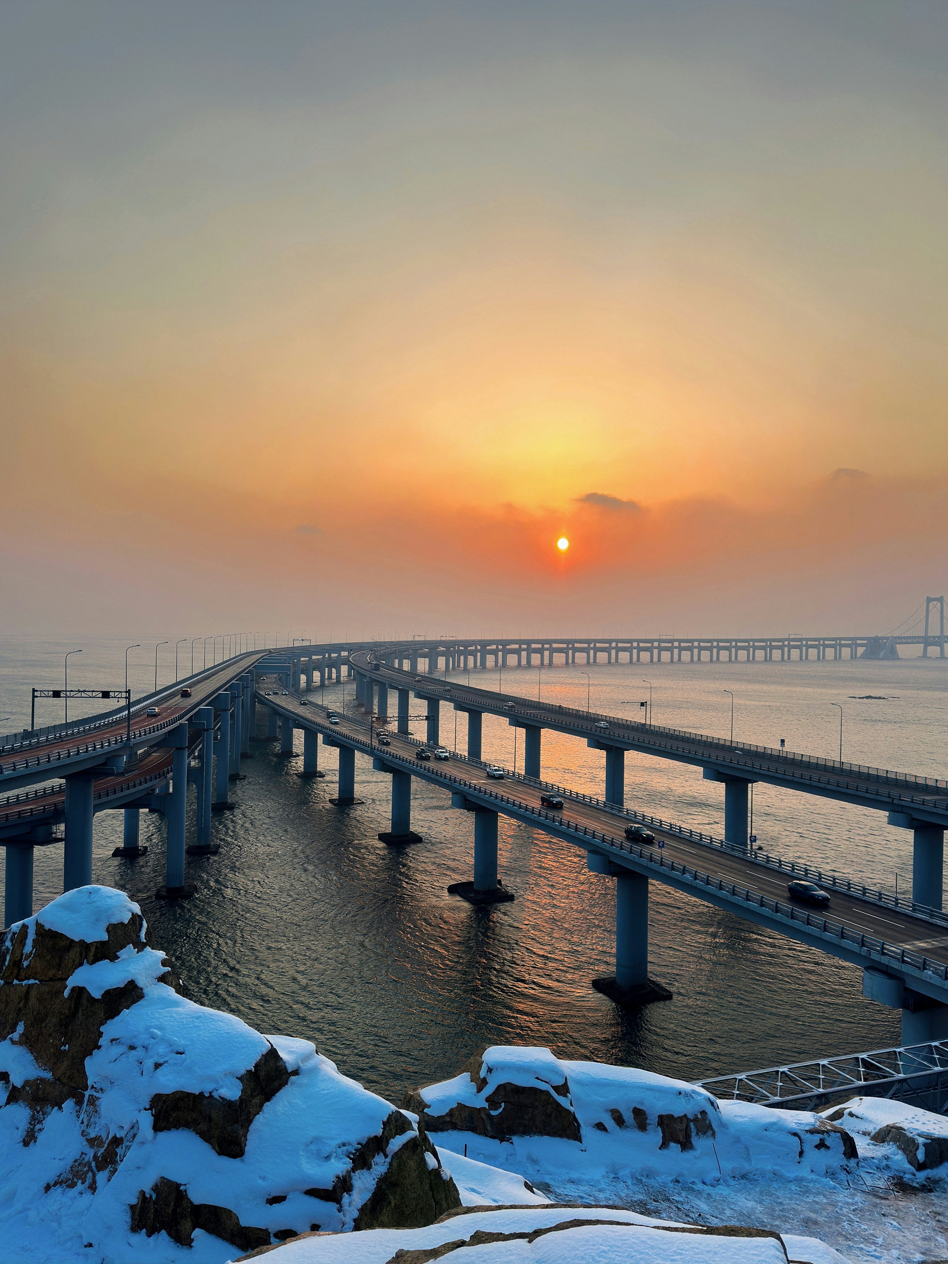 The sun is setting over a bridge over a body of water photo – Free ...