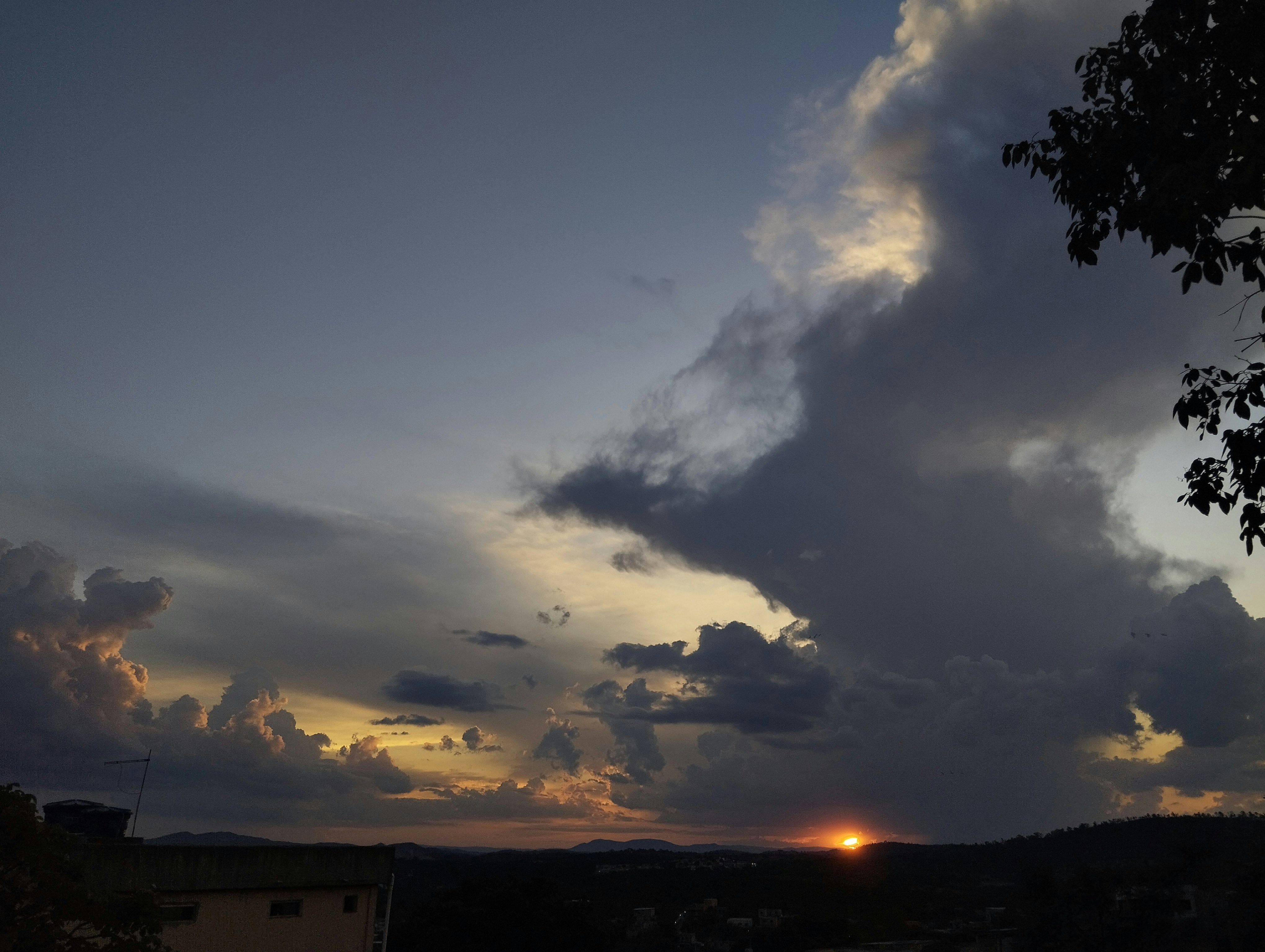 Sunset with dramatic clouds and a glowing horizon over a dark landscape.
