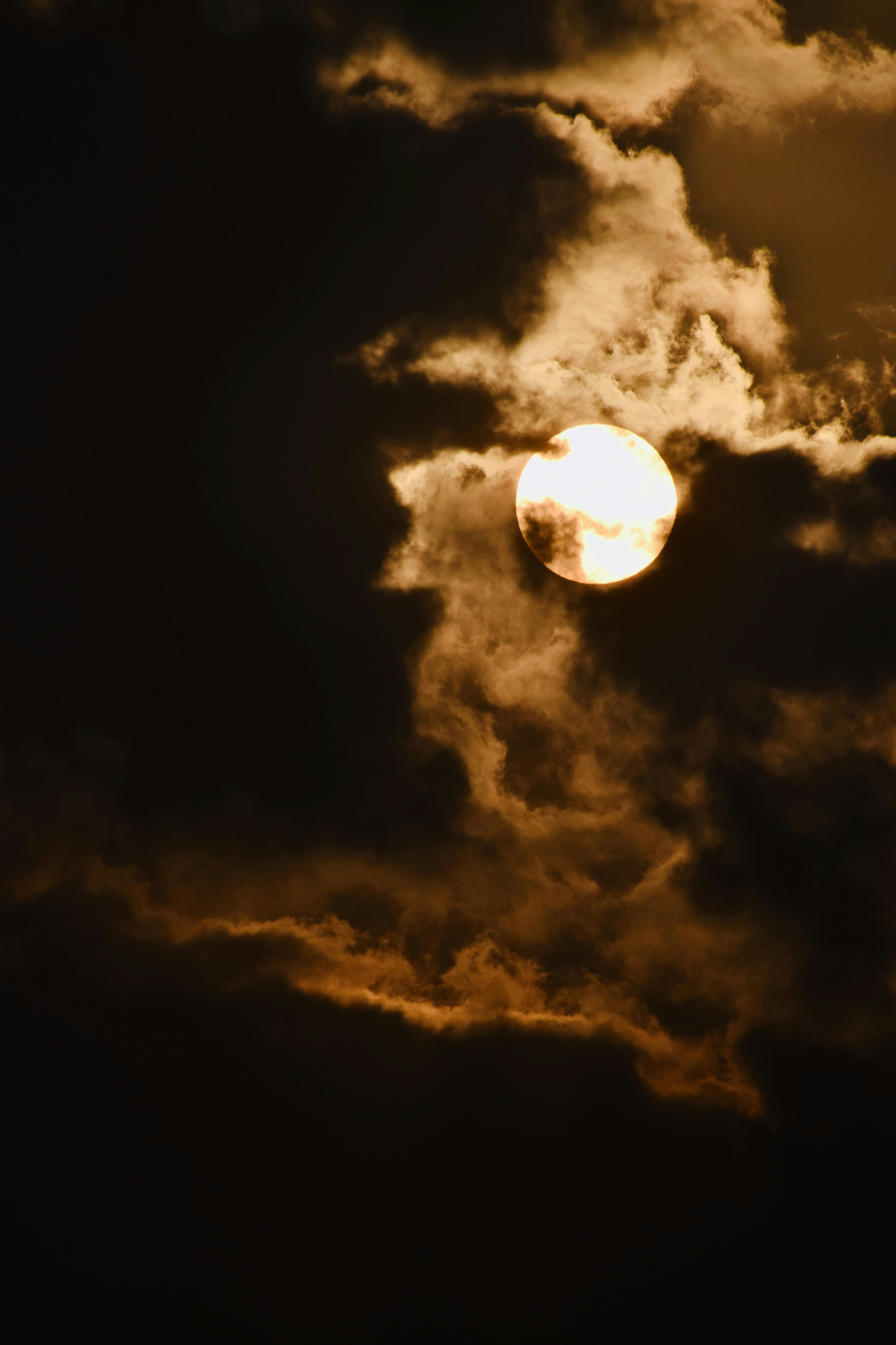 Sun partially obscured by dramatic clouds, casting a golden glow.