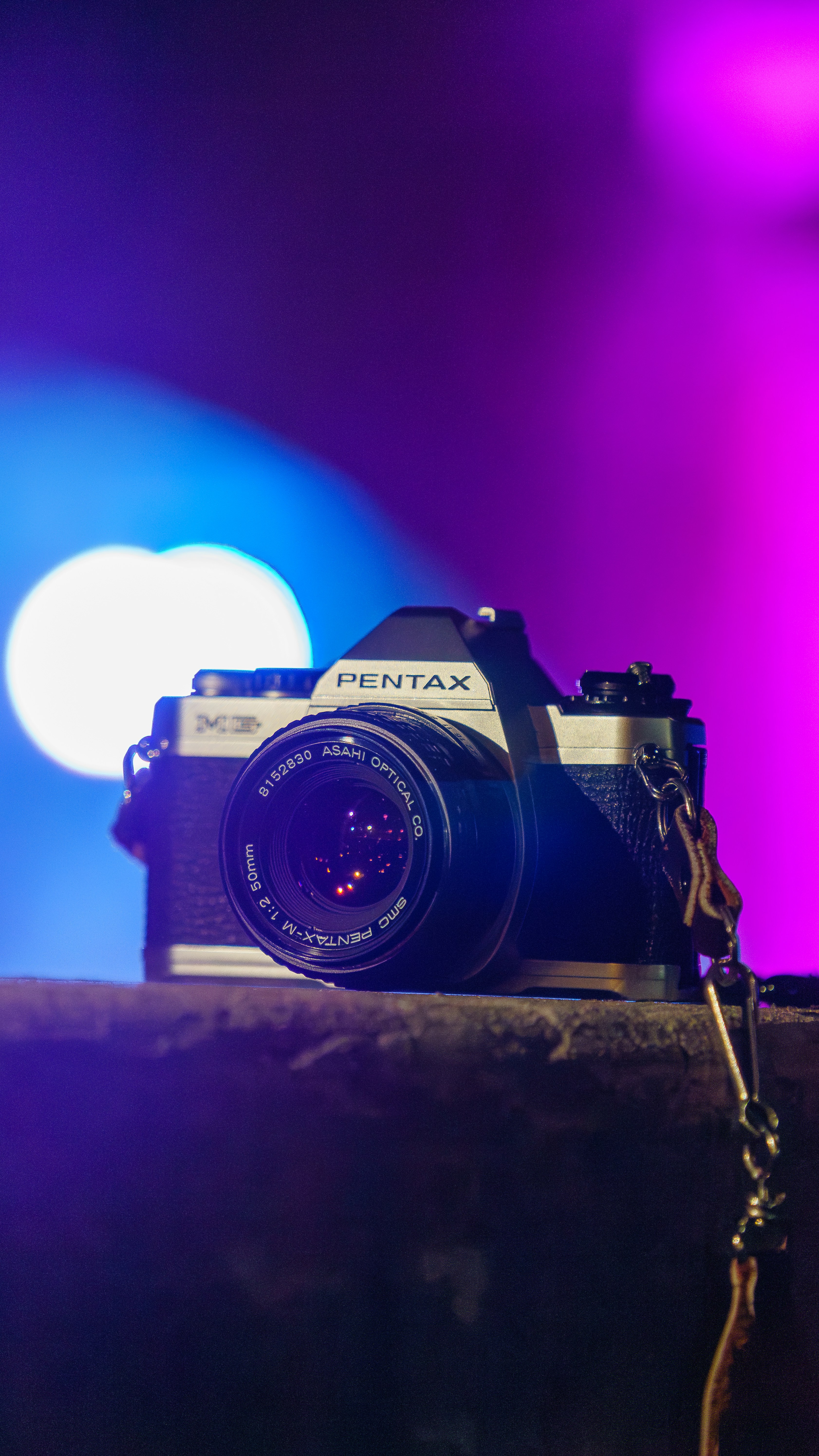 Neon Backdrop, Timeless Gear: A Pentax on a Velvet Ledge