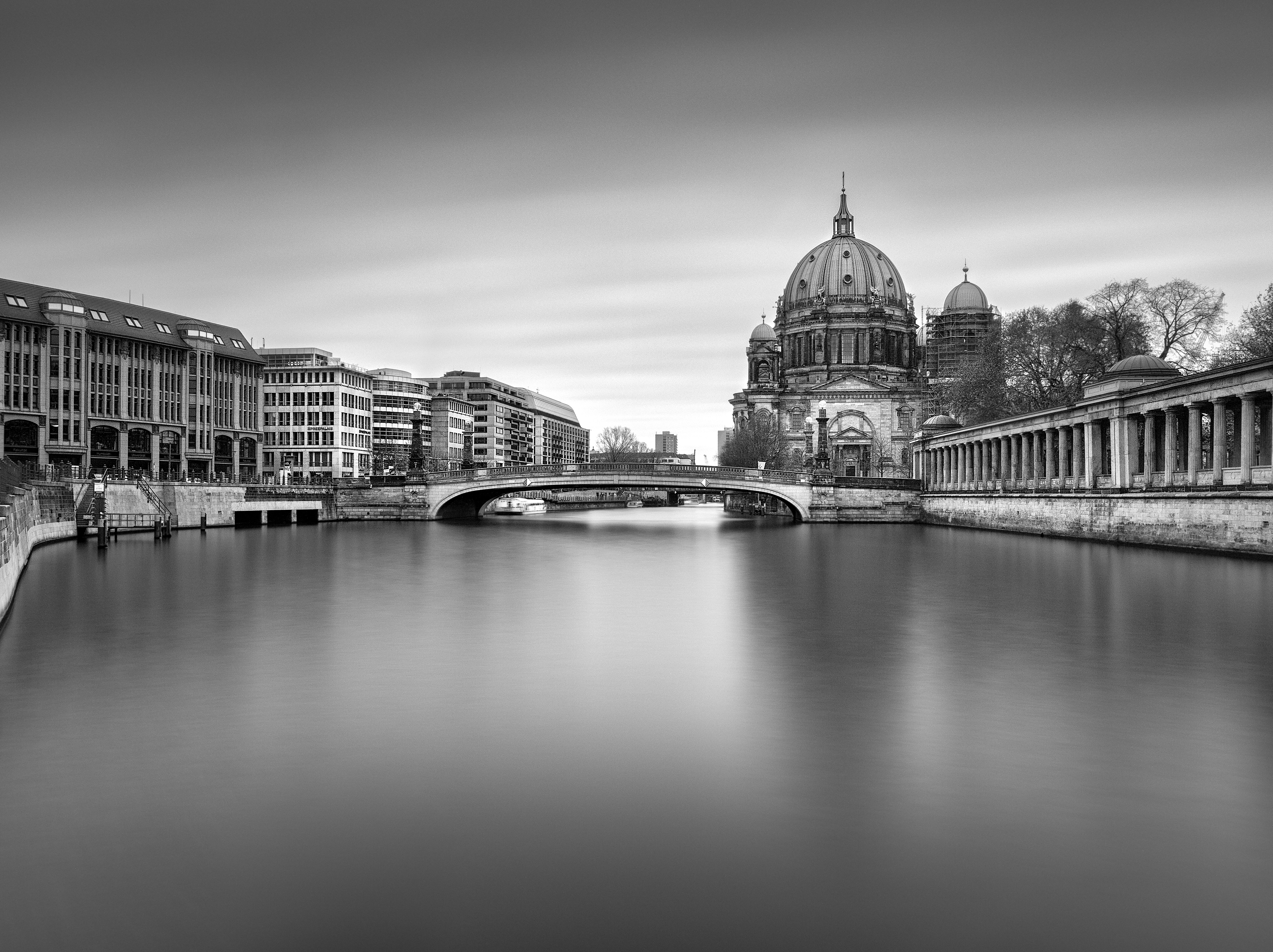 Berlin Cathedral and bridge over a calm river in black and white.