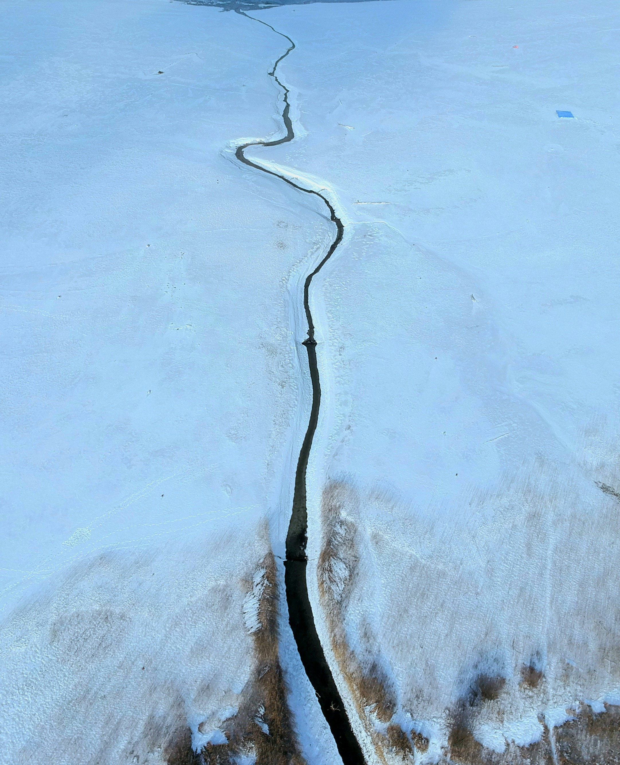 Glacial Suture: A Narrow Crevasse Winding Through Arctic Ice