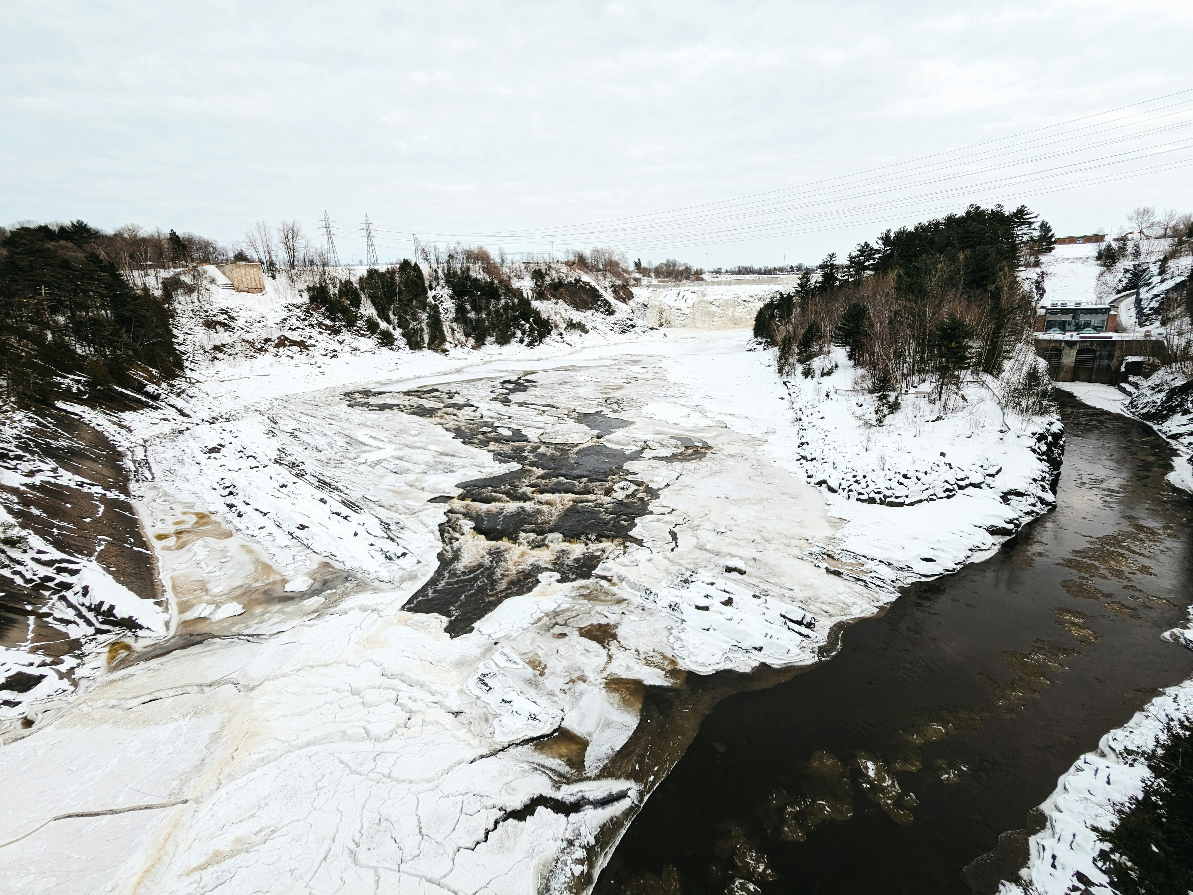 Icy Gorge: A Dark River Winding Through Snow-Capped Cliffs