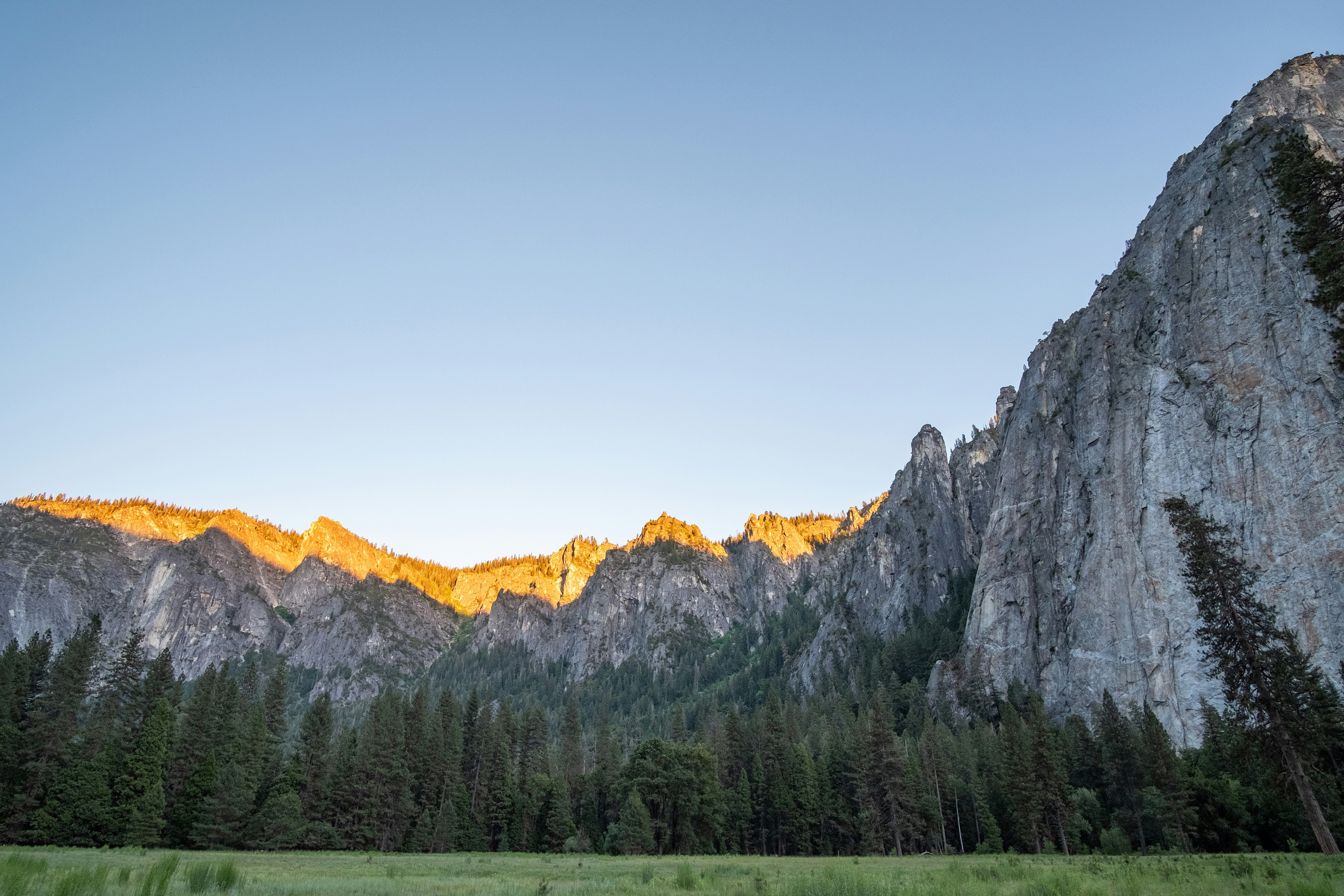 Alpenglow on jagged ridges above a quiet meadow