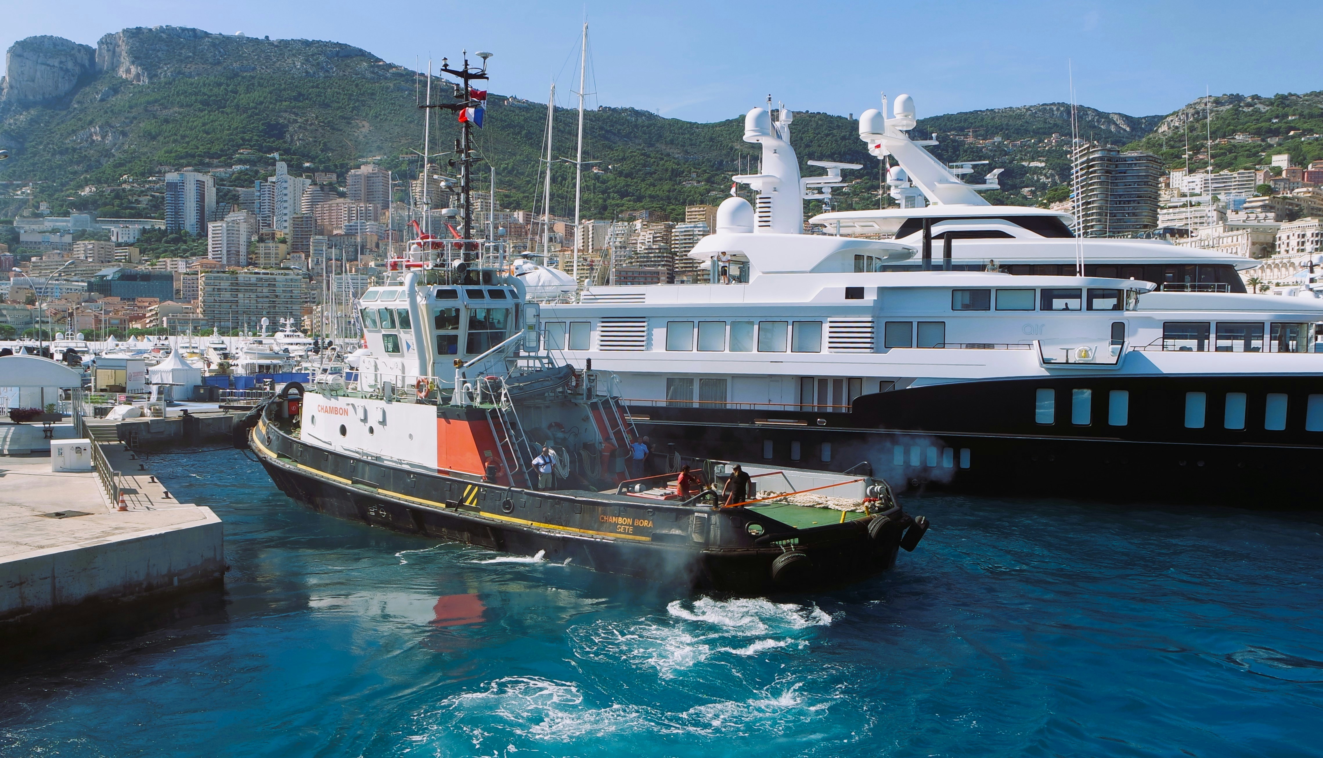 Edge of the Harbor: Tugboat Beside a Gleaming Mega-Yacht