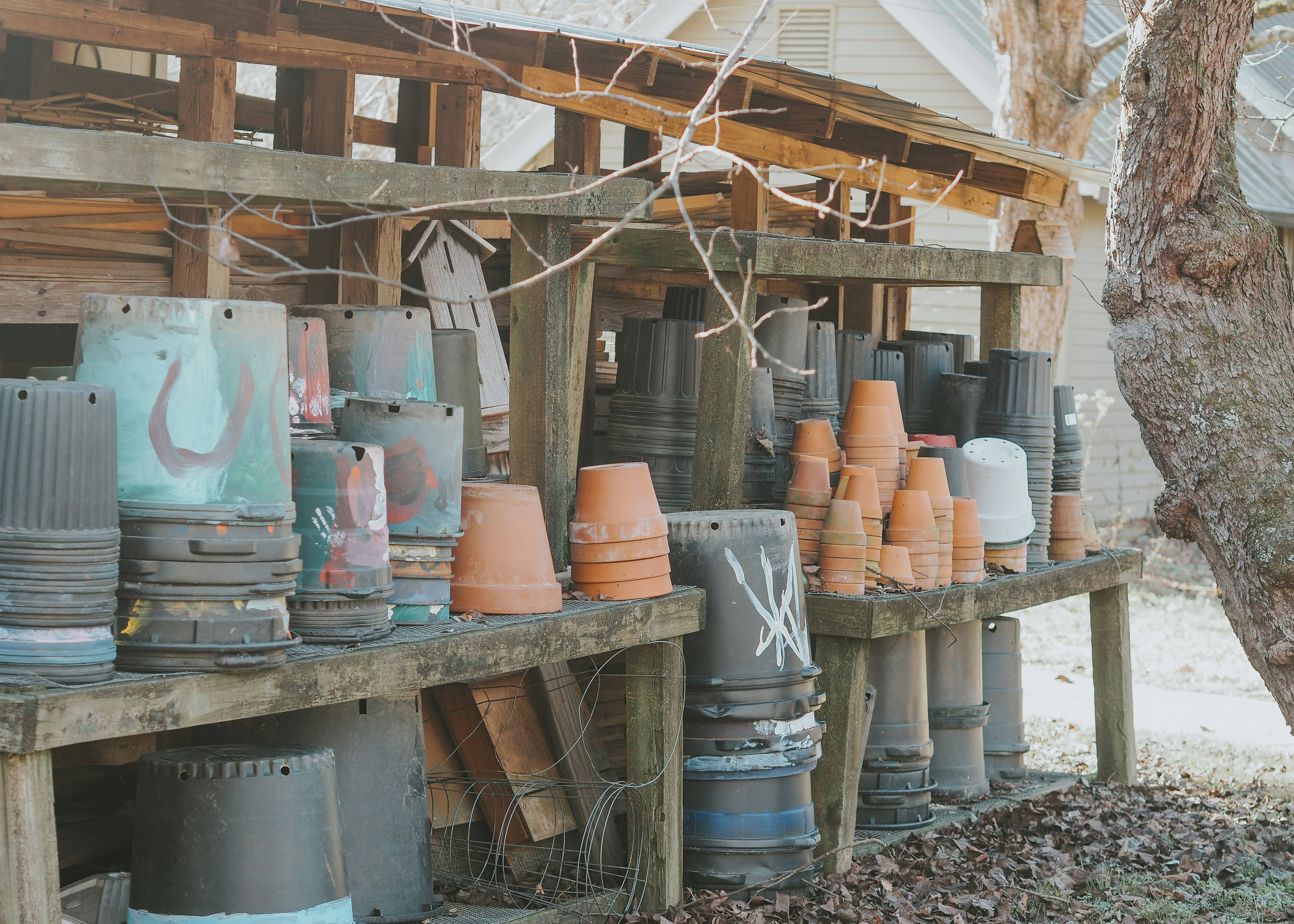Sheltered Pots: A Quiet Mosaic of Colorful Containers Along a Weathered Deck