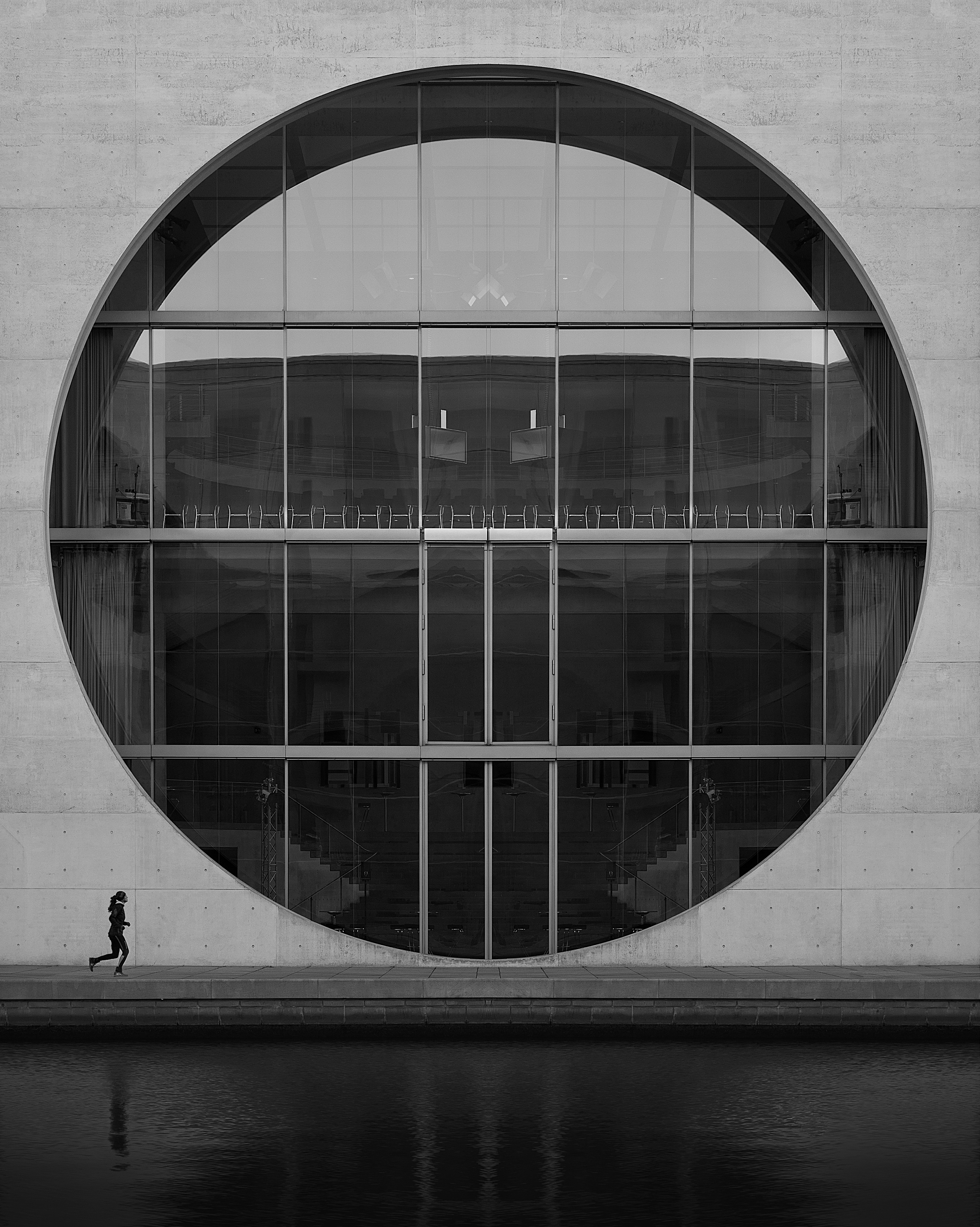 Solitary Jogger Glides Past a Colossal Circular Glass Facade