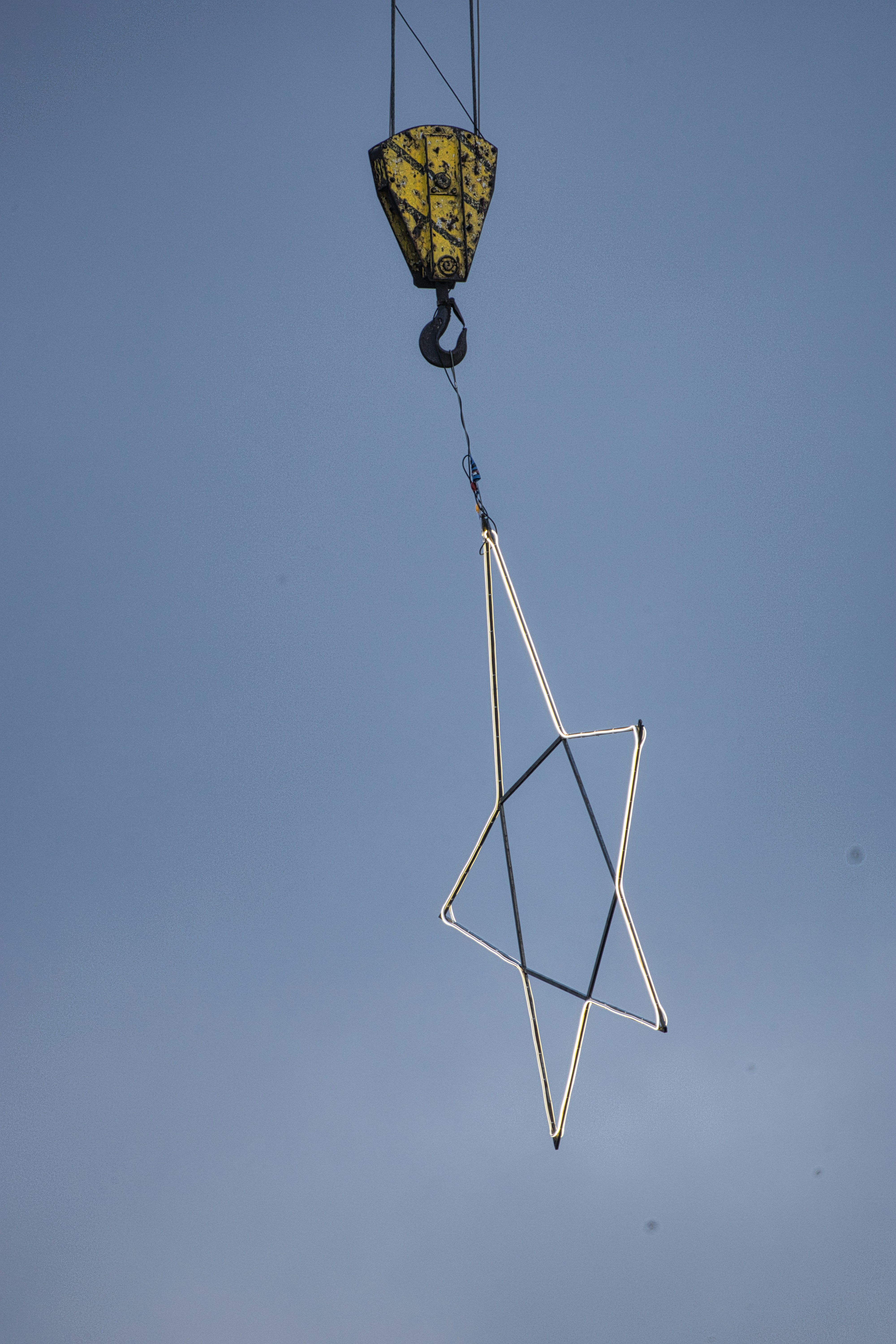 Drifting Neon Star: A Crane-Hung Light Sculpture in a Clear Blue Sky