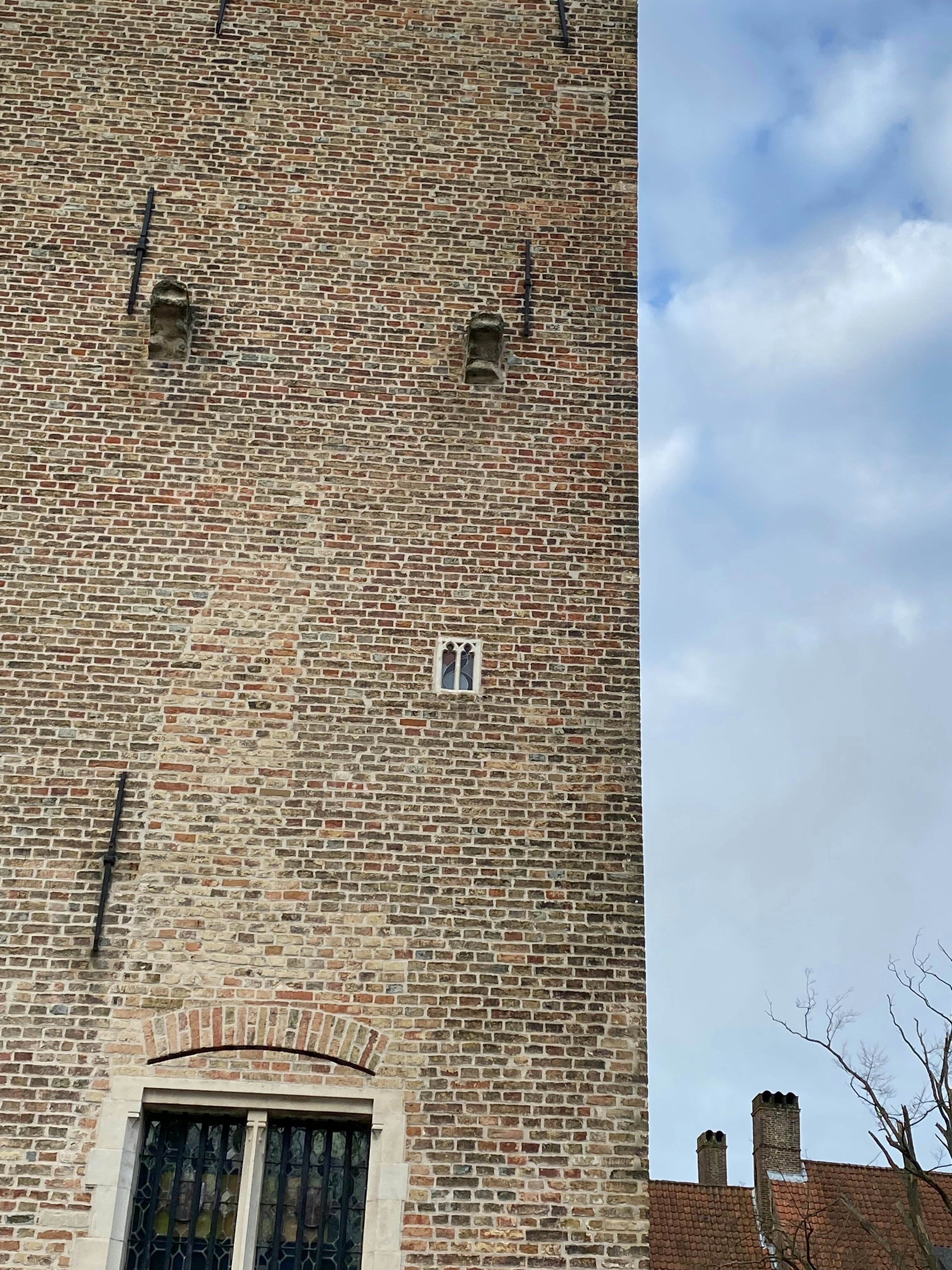 Brick Tower Corner with Narrow Window Details Against a Blue Sky