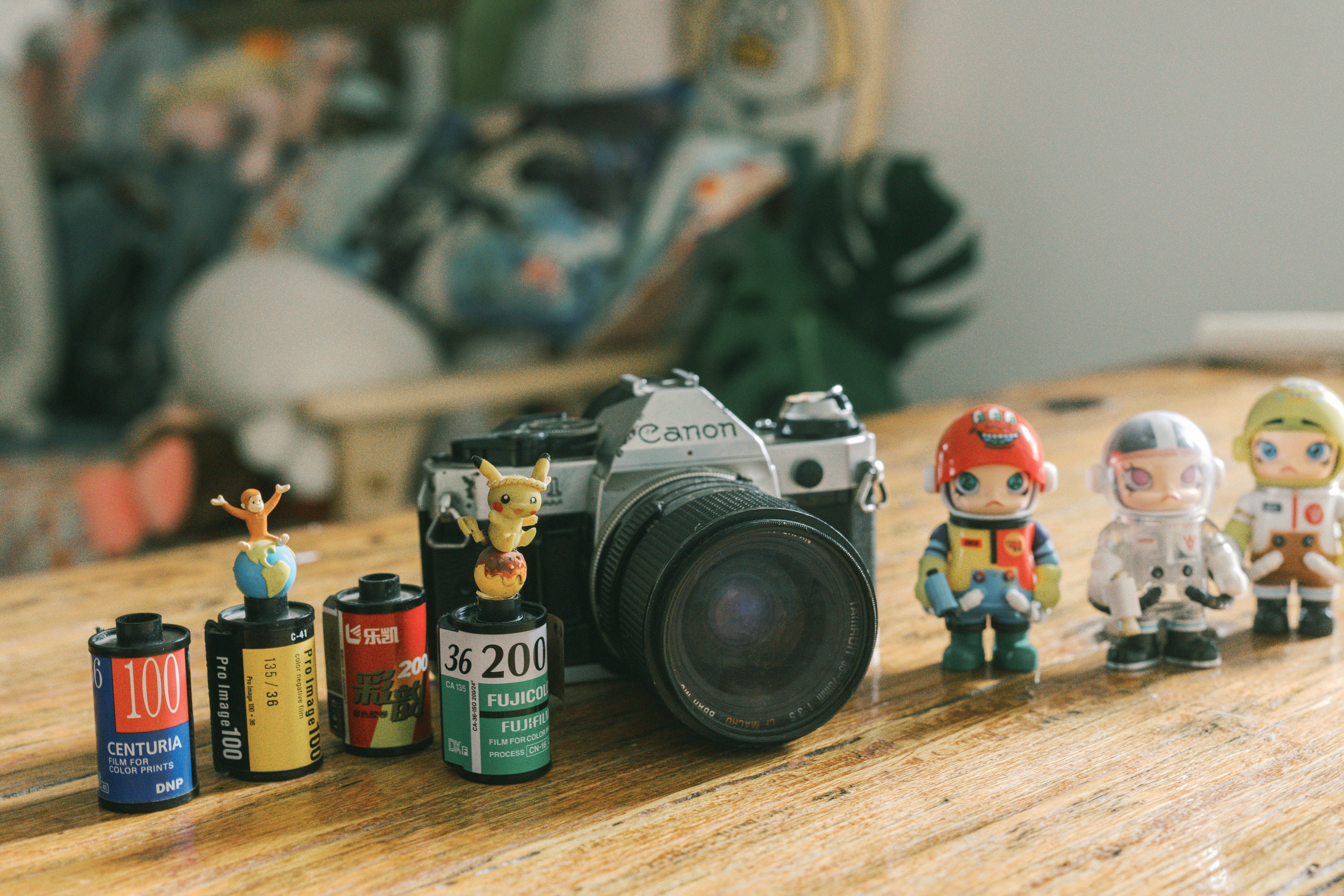 Central Lens, Tiny World: A Canon on a Table of Film Canisters and Figurines