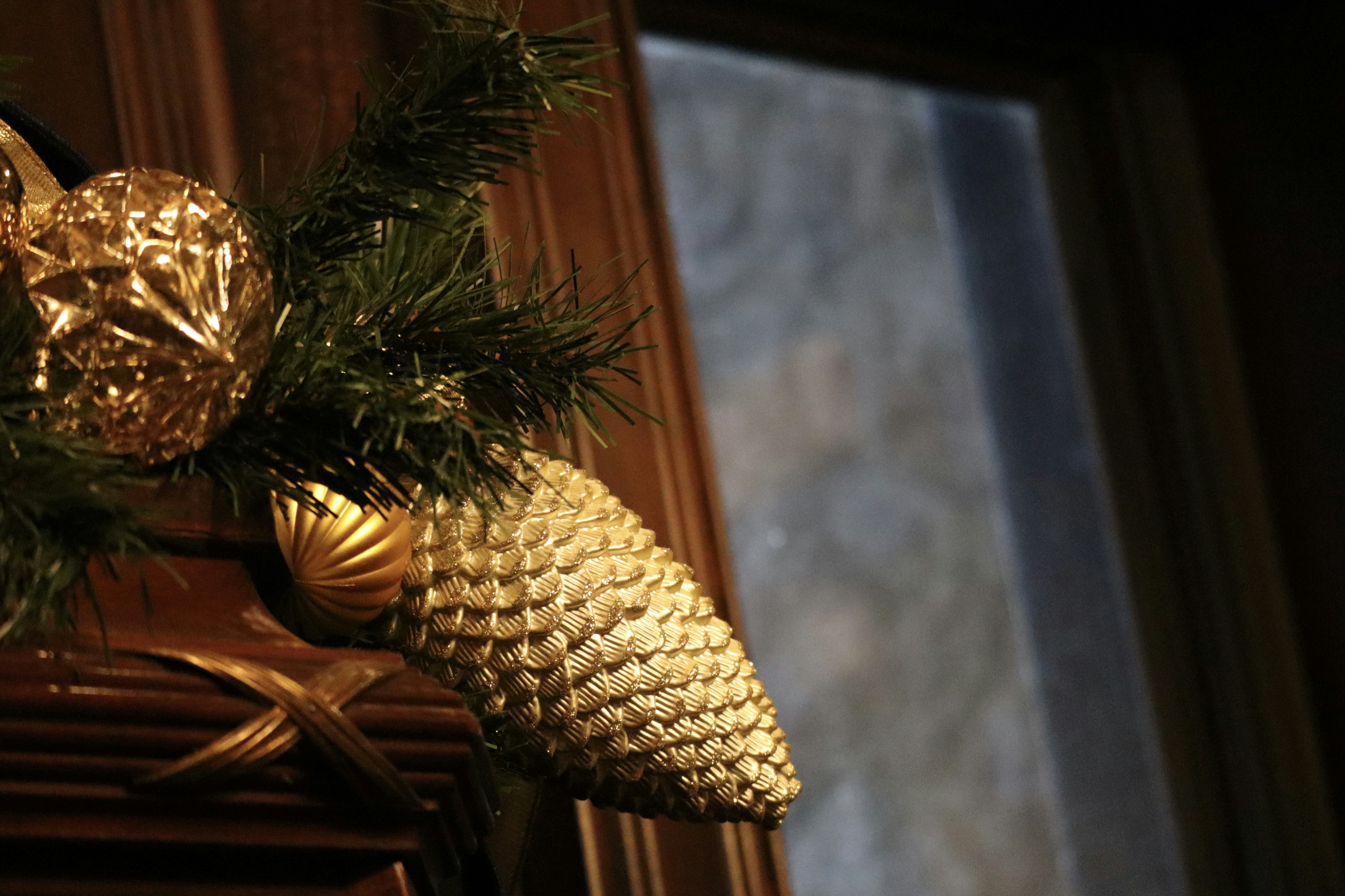 Gilded Pinecone on a Walnut Mantel Beneath Warm Indoor Glow