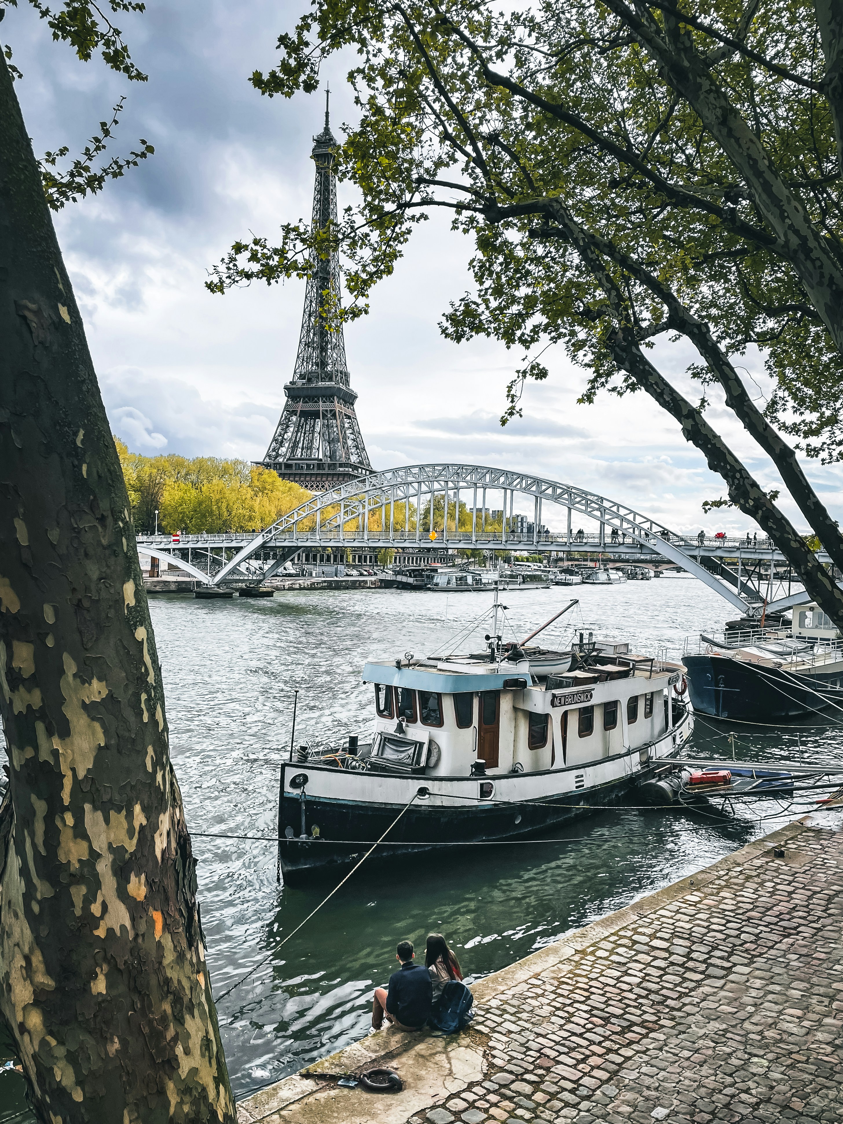 A couple takes a break by the river Seine near the Eiffel Tower in Paris