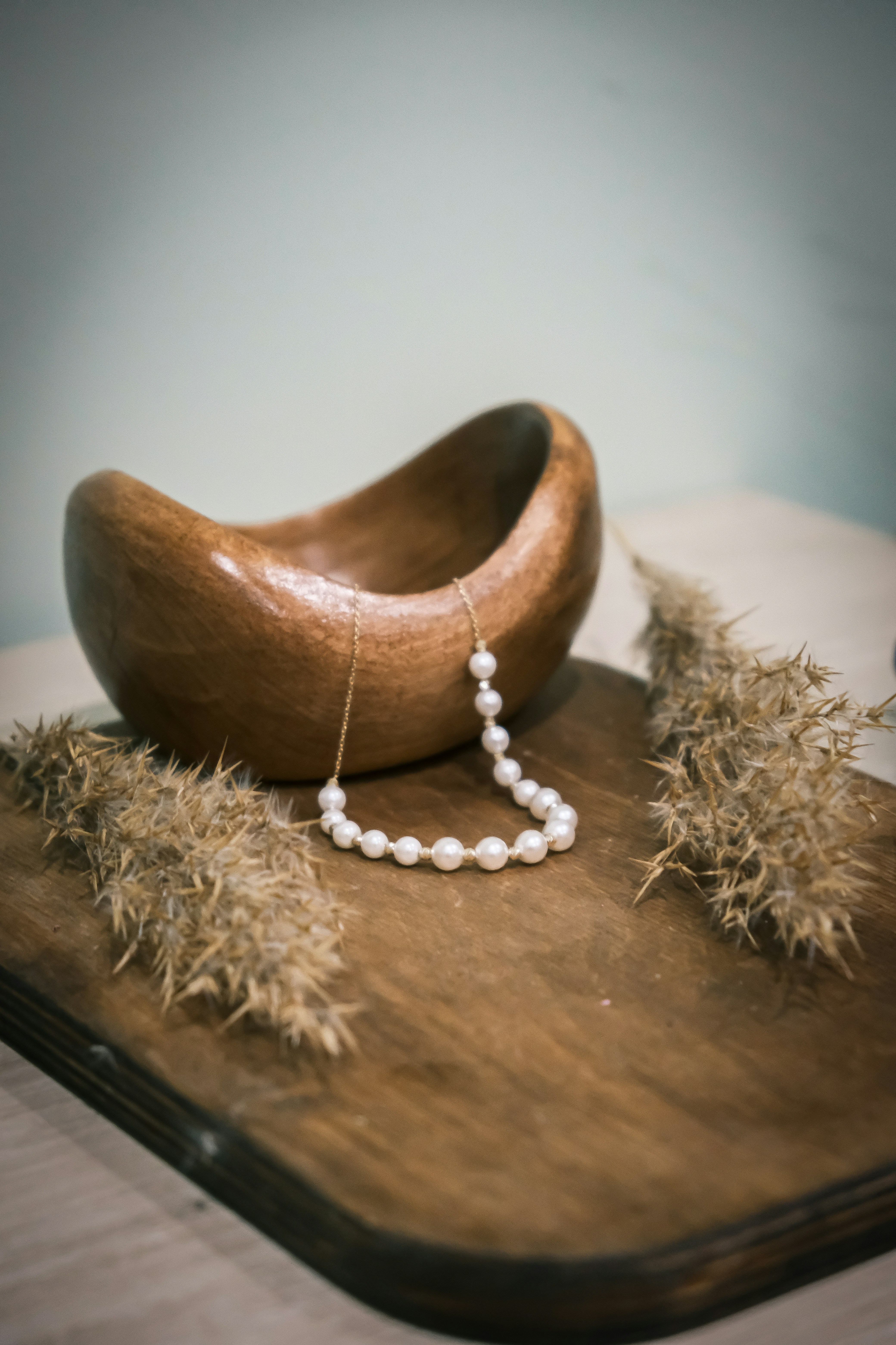 Pearl Necklace Draped Across a Weathered Wooden Tray