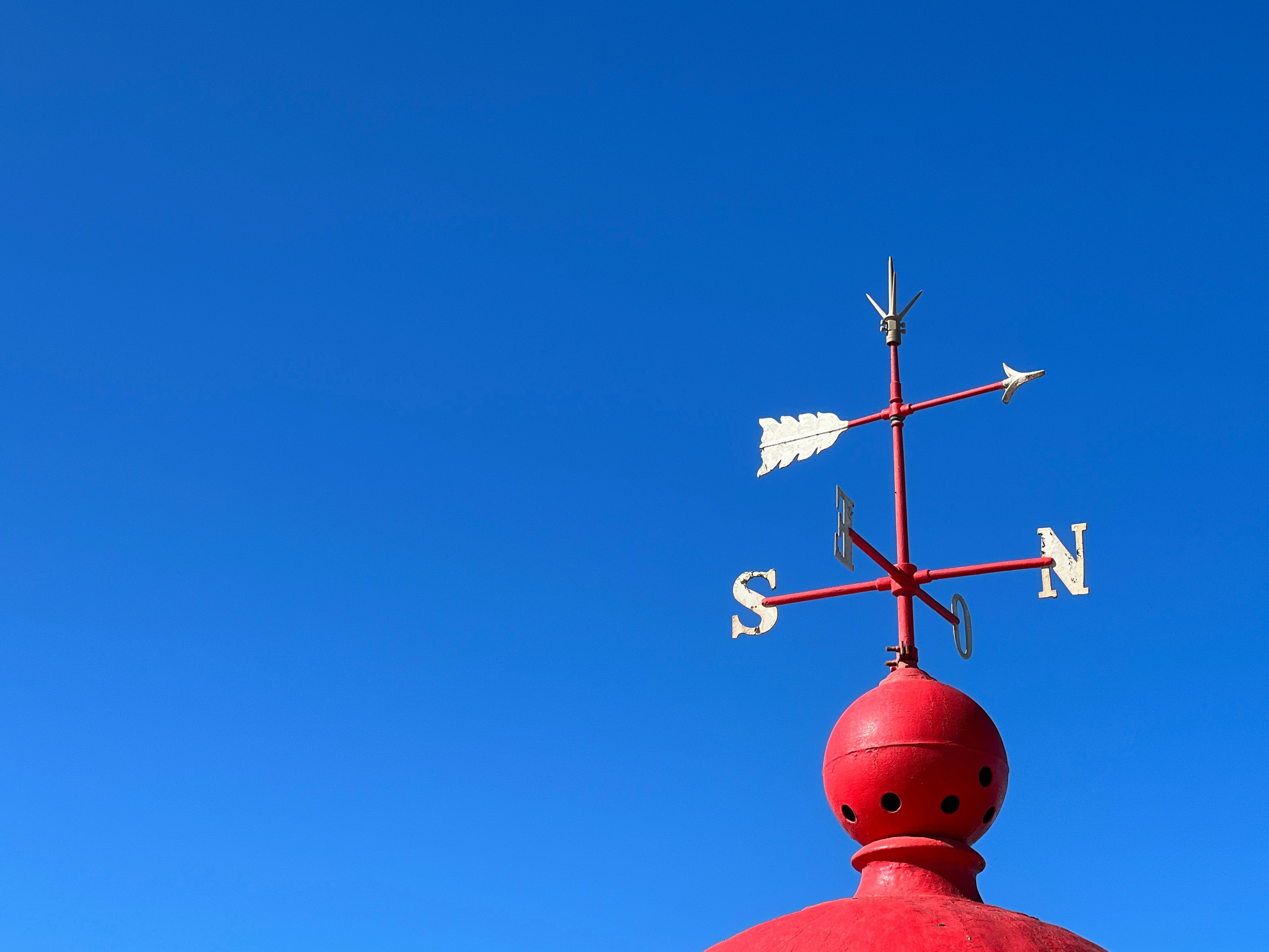 A weather vane on top of a red building photo – Free Human Image on ...