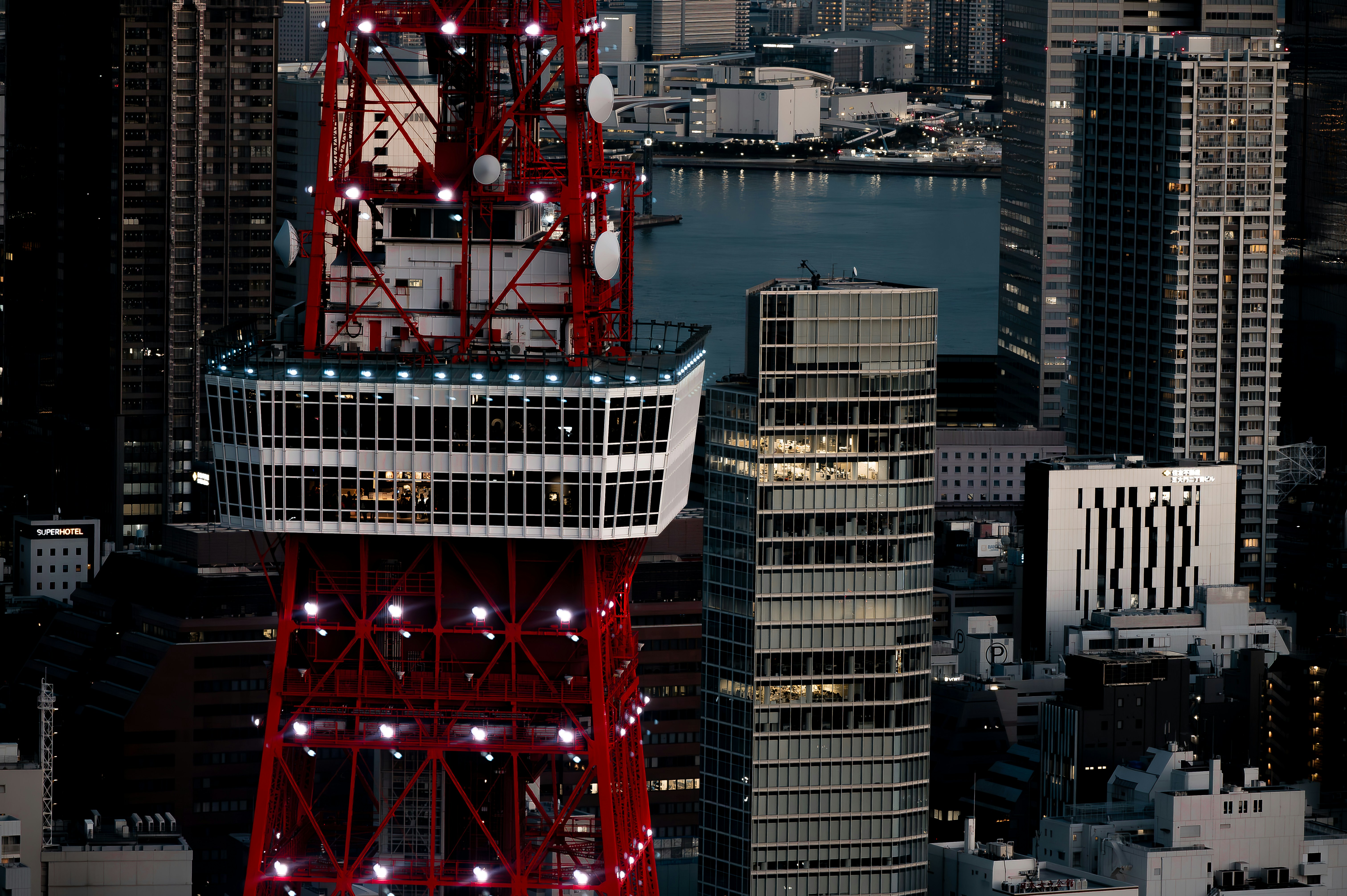 Crimson Lattice Tower Framing a Neon City at Dusk