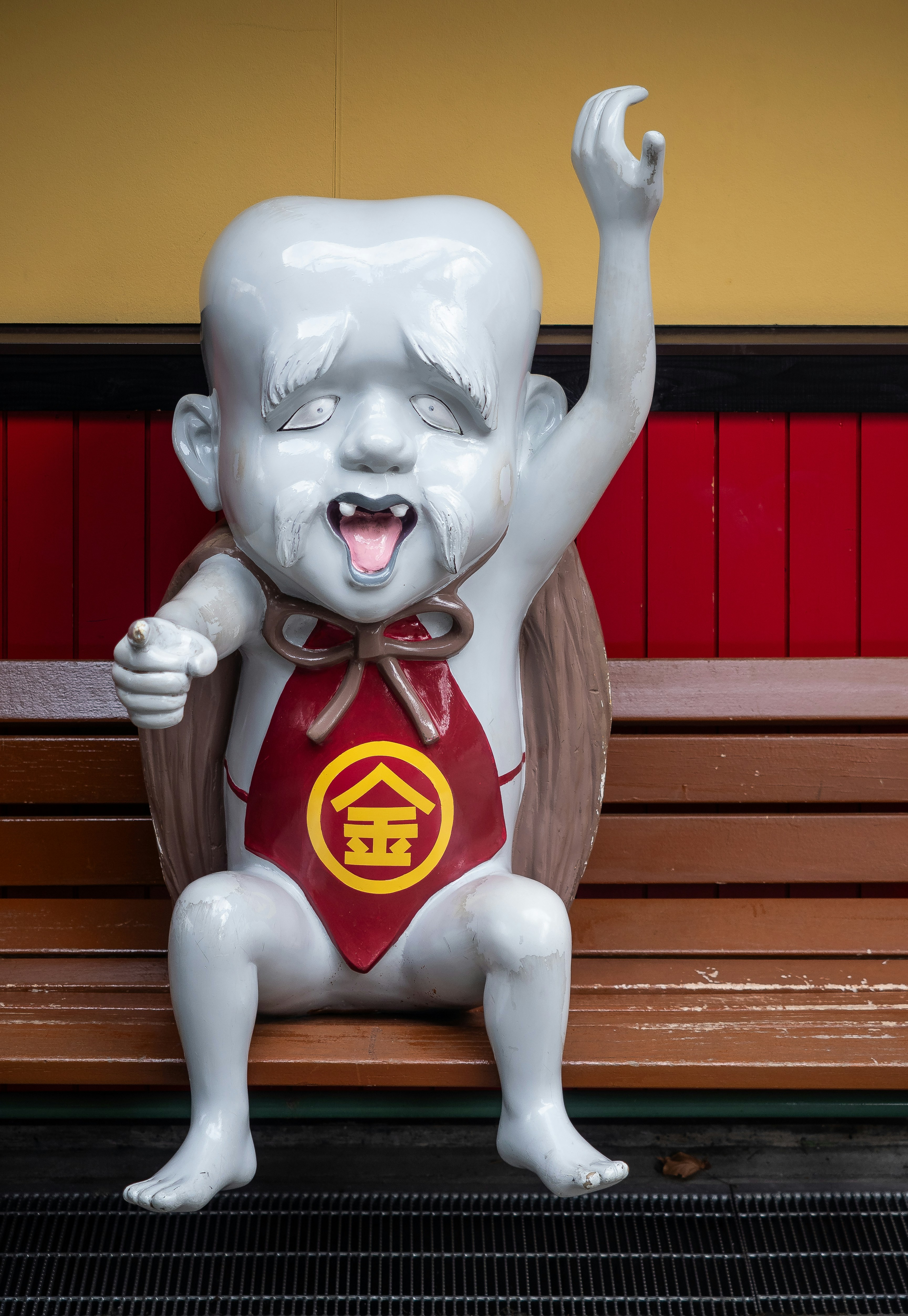 Joyful Bust on a Red Bench: A White Ceramic Figure with Raised Arm