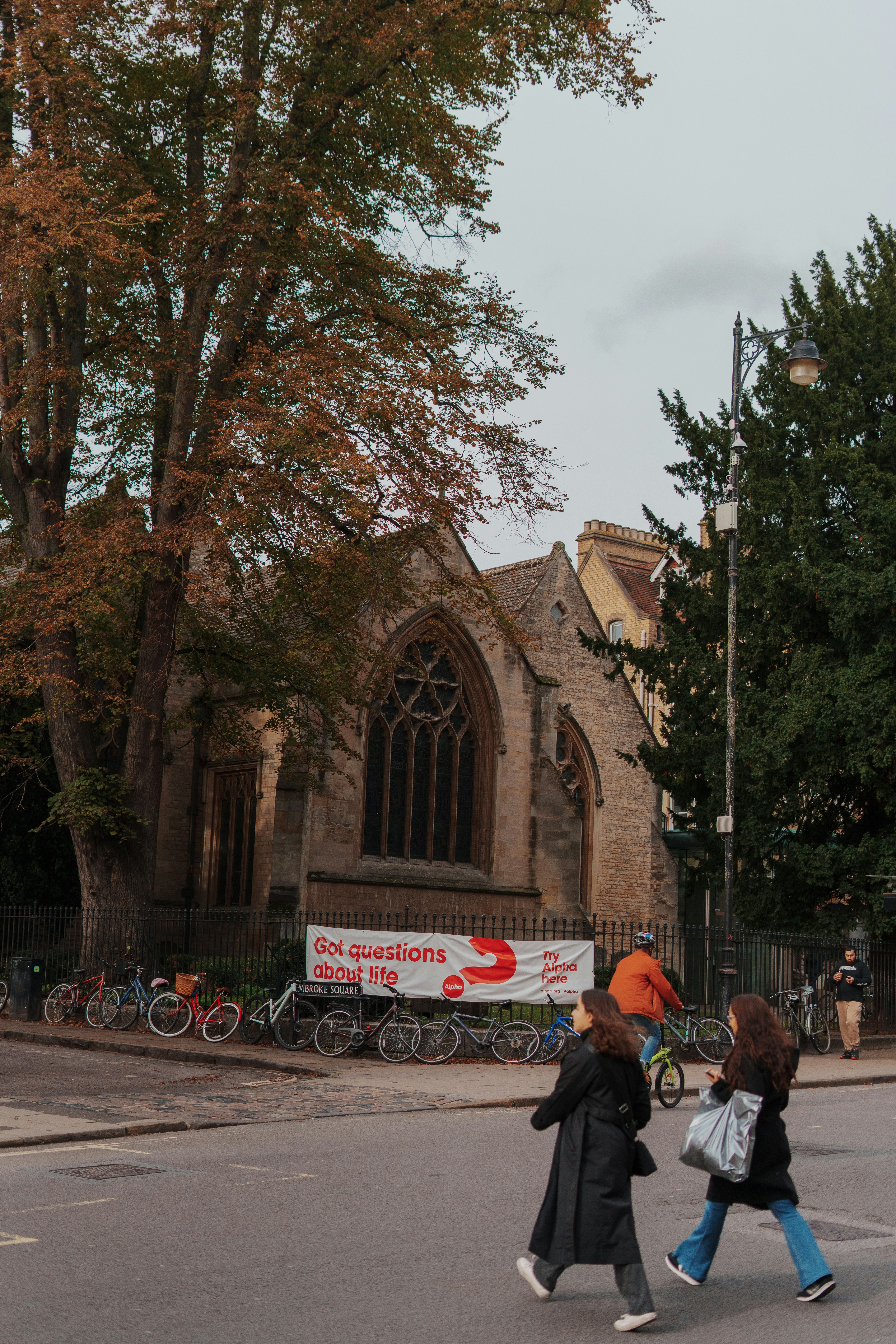Campus Scene: A Stone Church Framed by Autumn Trees and Passing Pedestrians