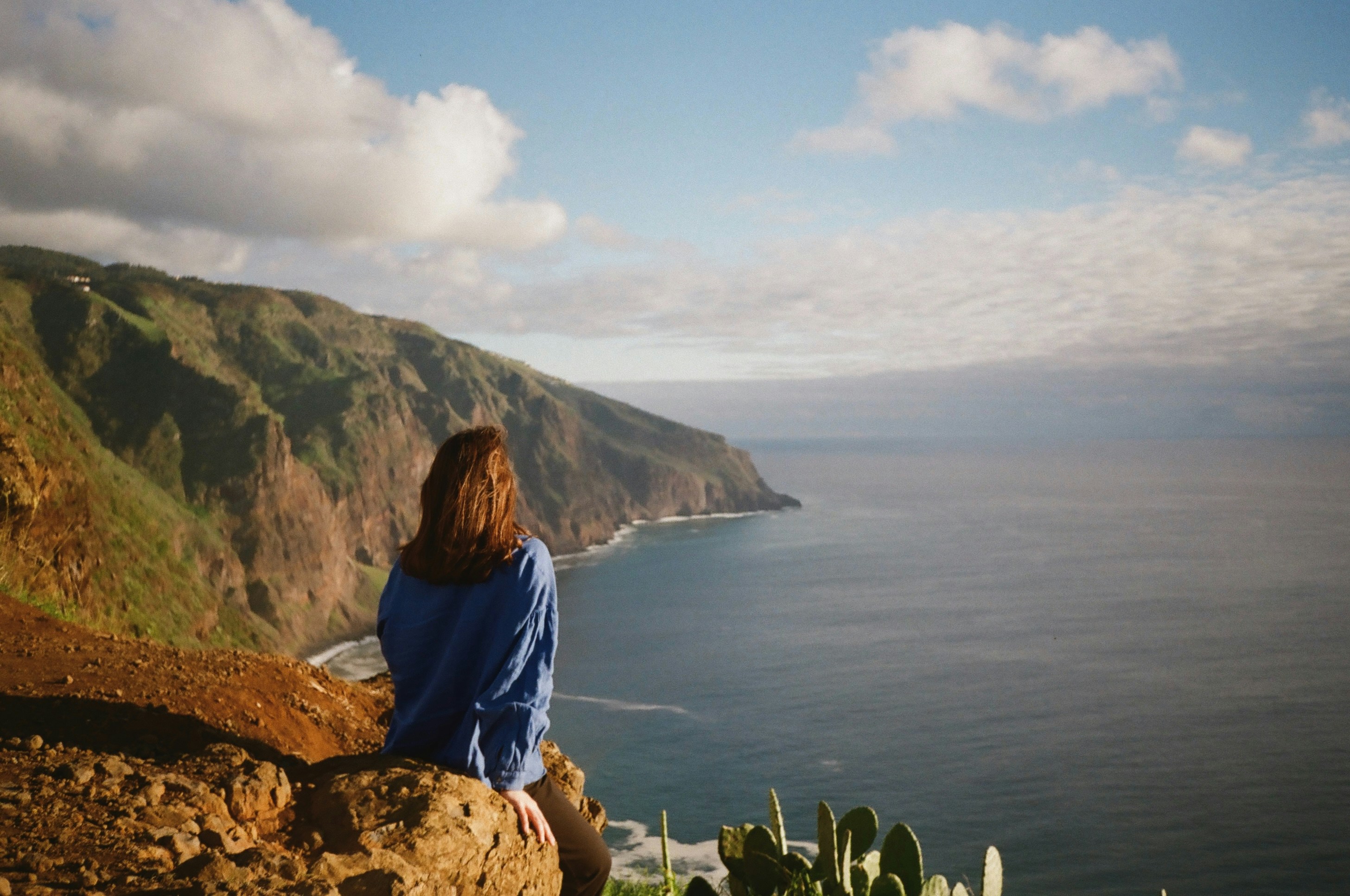 A woman sitting on a rock overlooking the ocean photo – Free Nature ...
