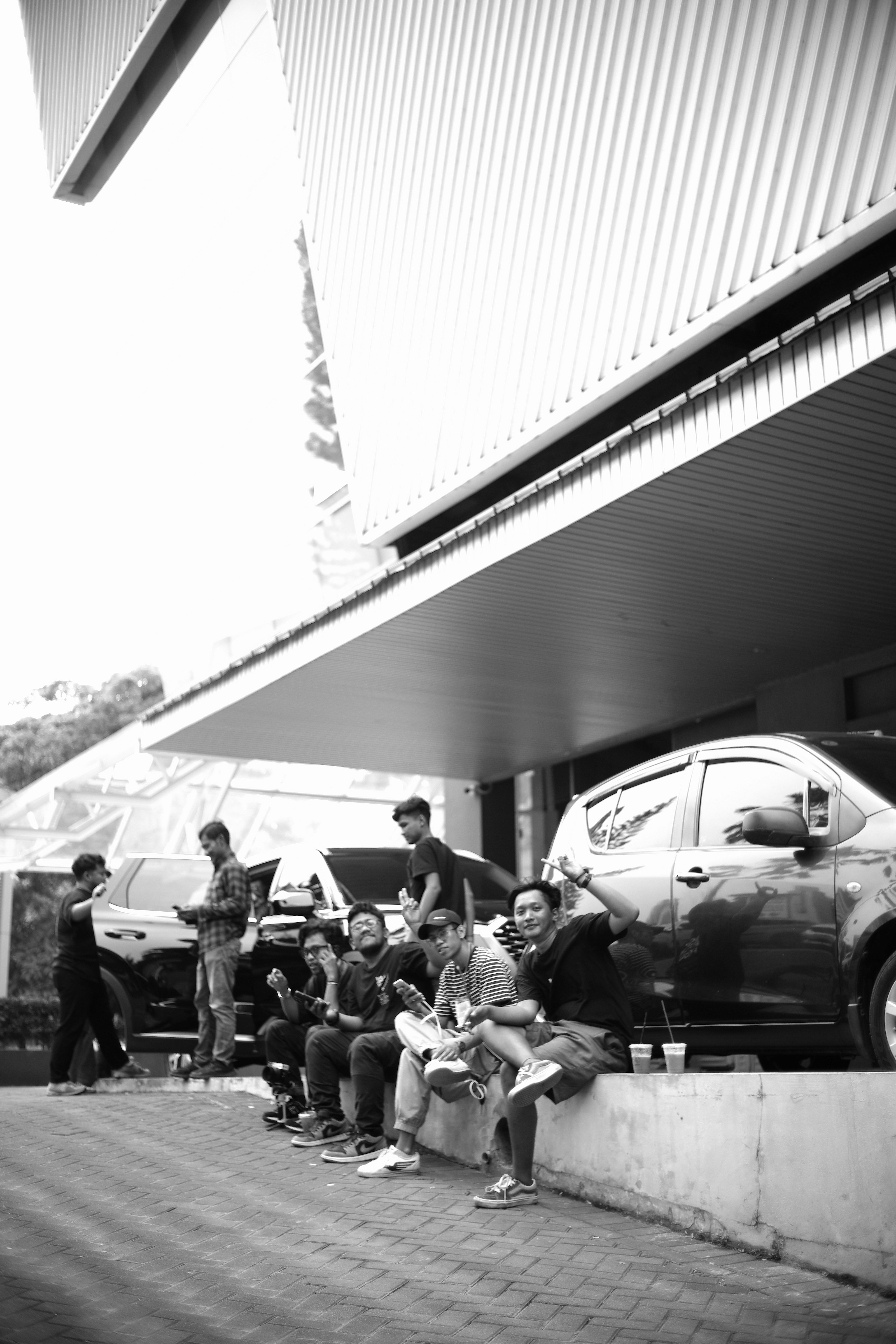 A group of people sitting on a curb next to a car photo – Free Machine ...