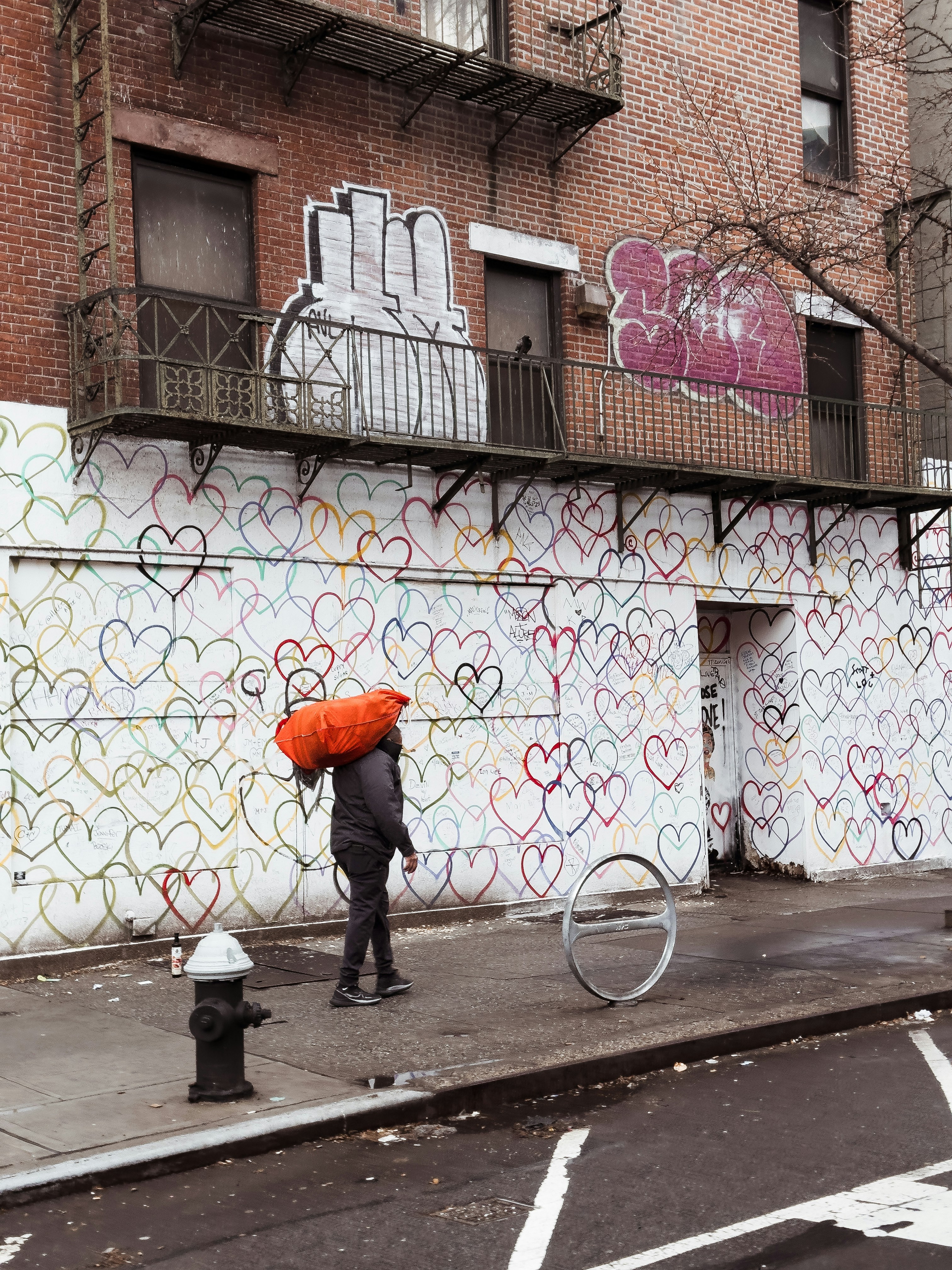 Orange Pack Walks Past a Heart-Walled Alley