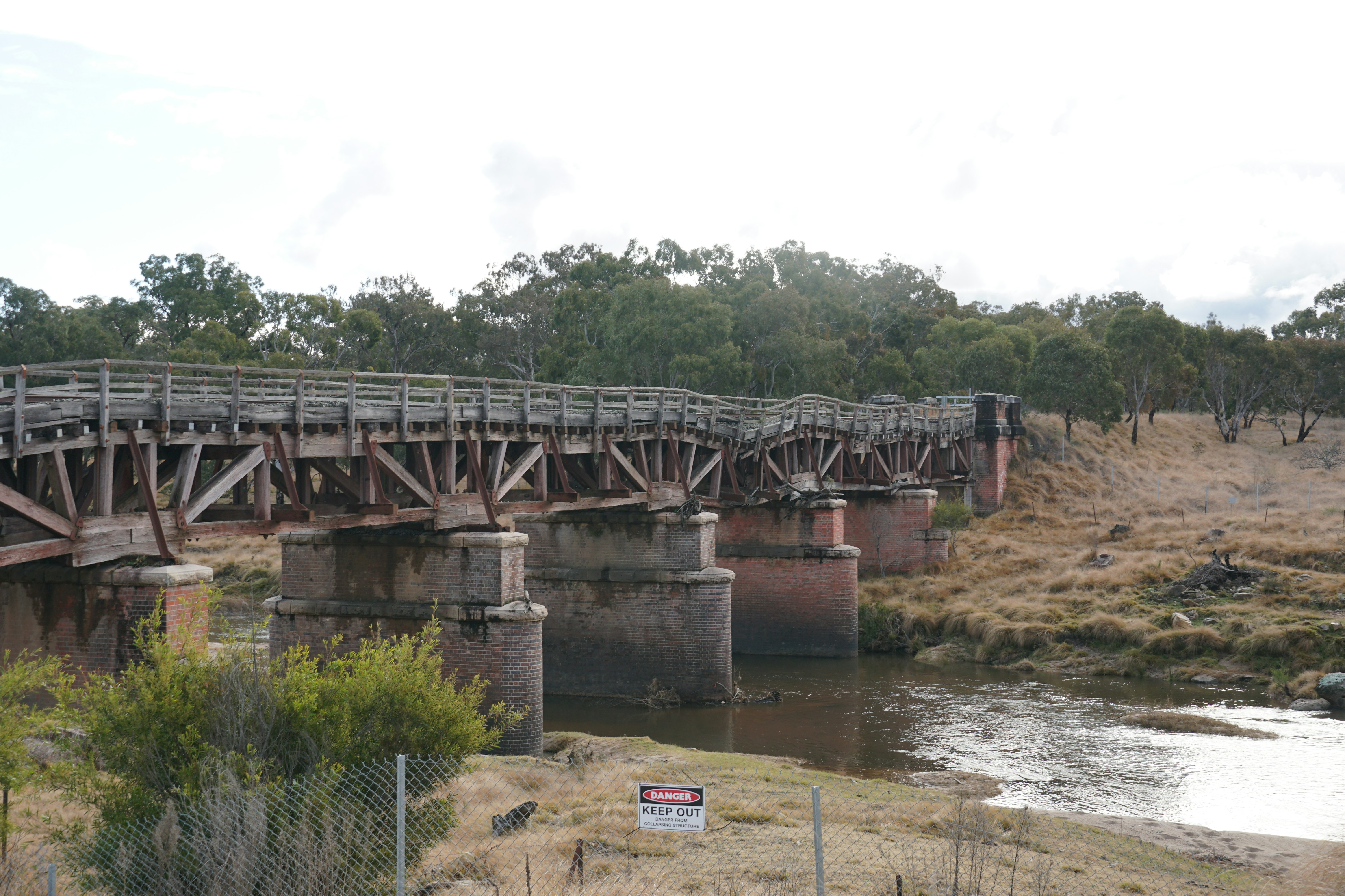 Weathered Timber Span Crossing a Quiet River in Dry Light