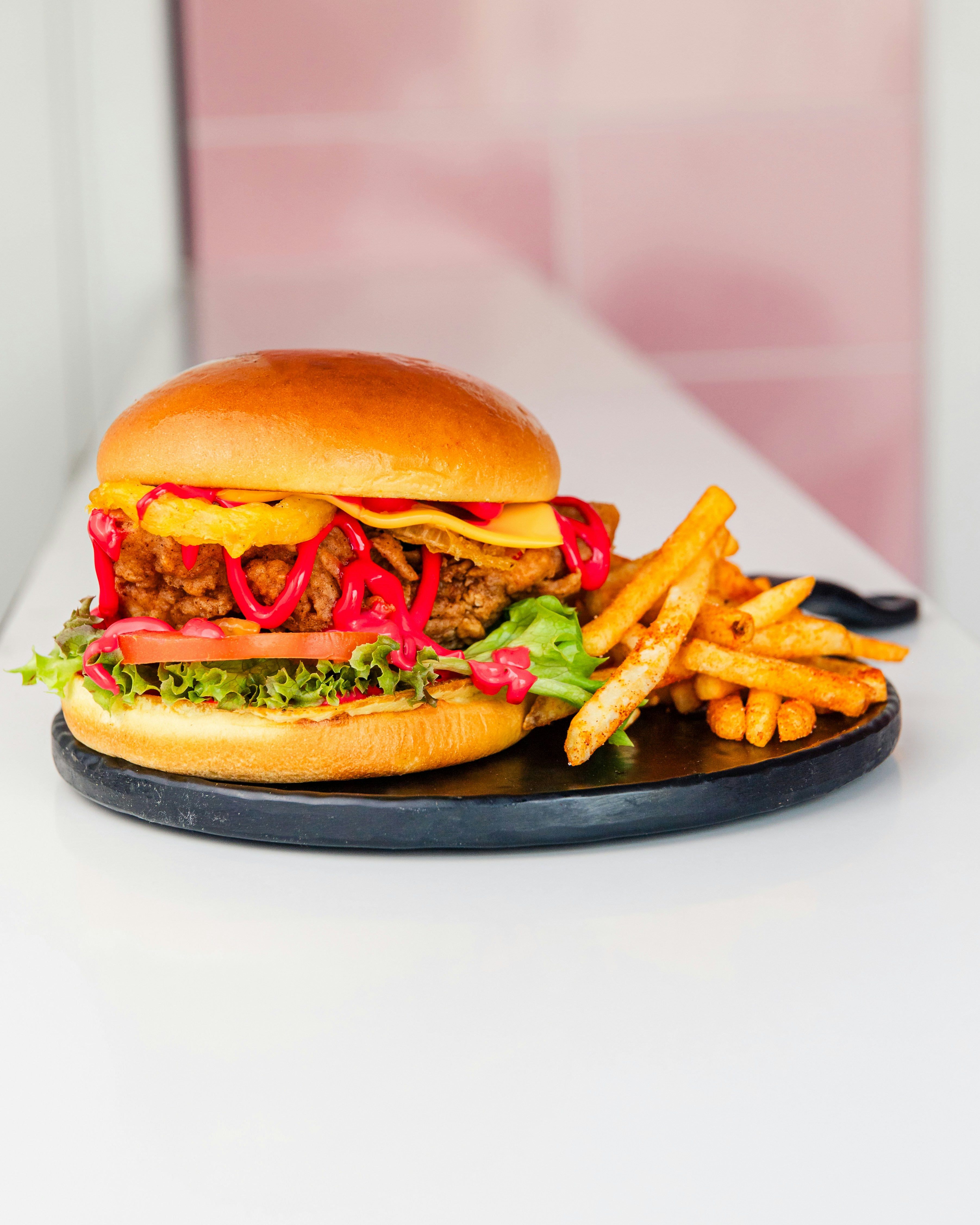 Slate-Plate Sizzle: Juicy Burger with Crispy Fries on Pink Tiles