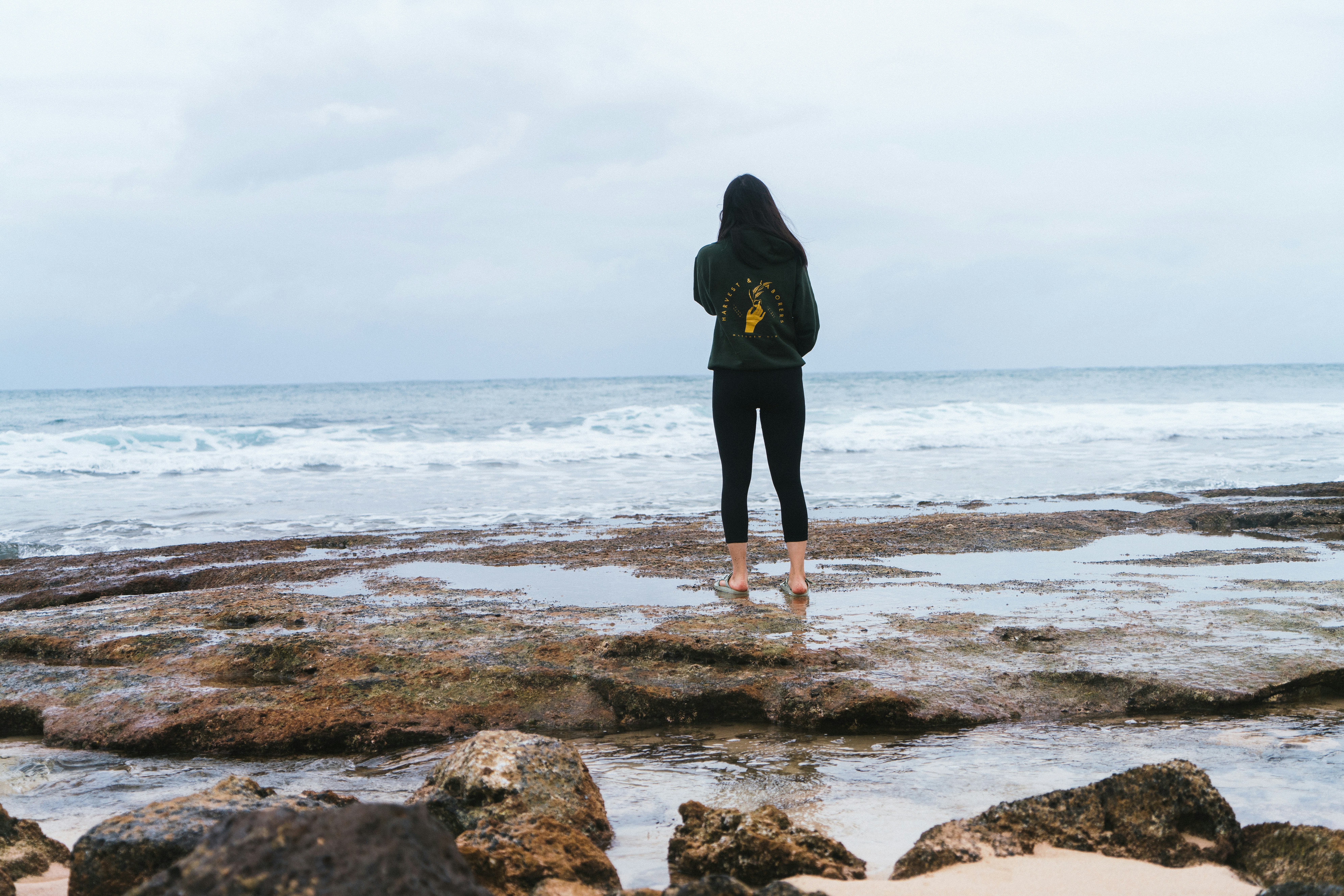 Barefoot at the Sea's Edge: A Quiet Silhouette on Weathered Rocks
