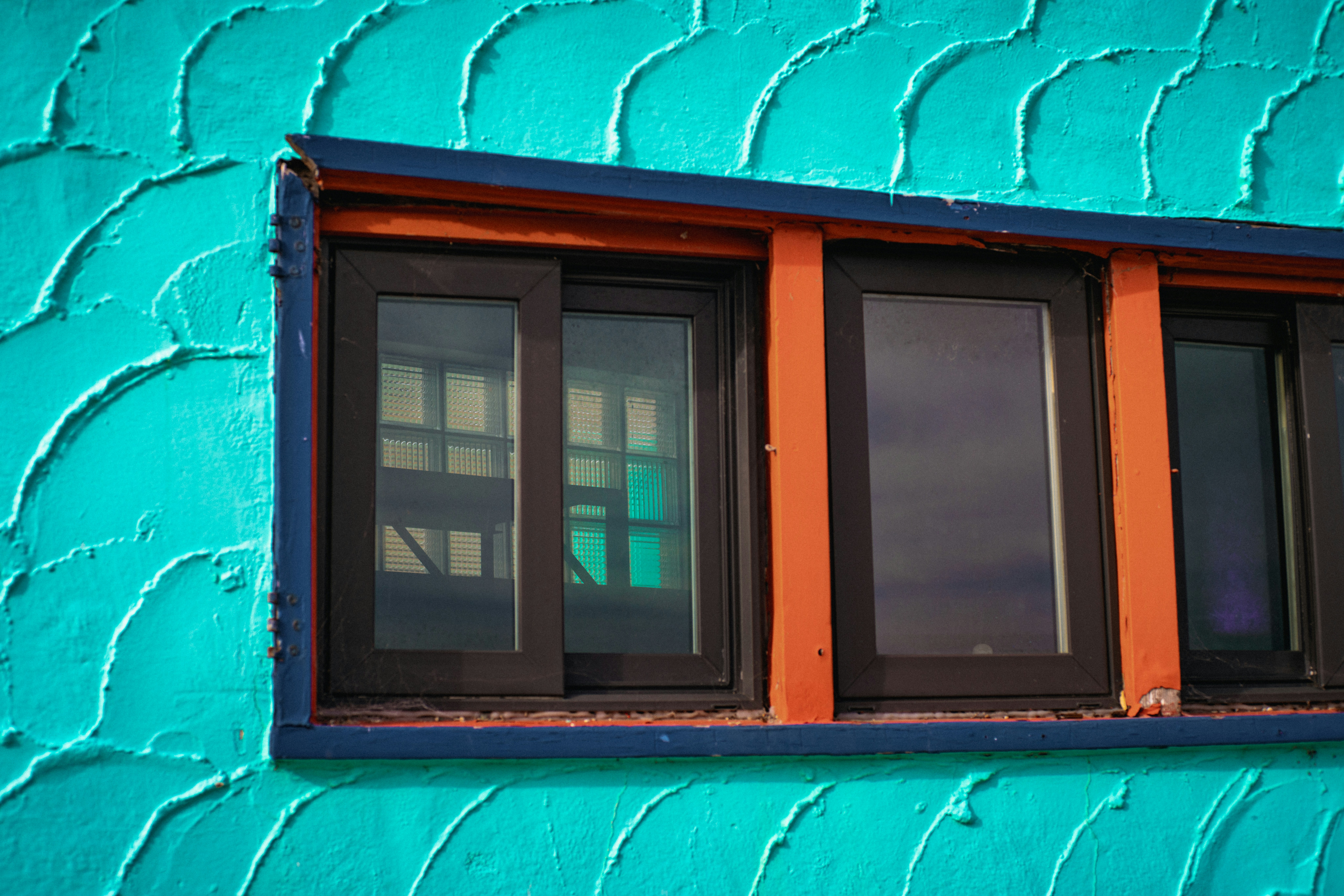 Orange-Framed Window Anchored on a Teal Textured Wall