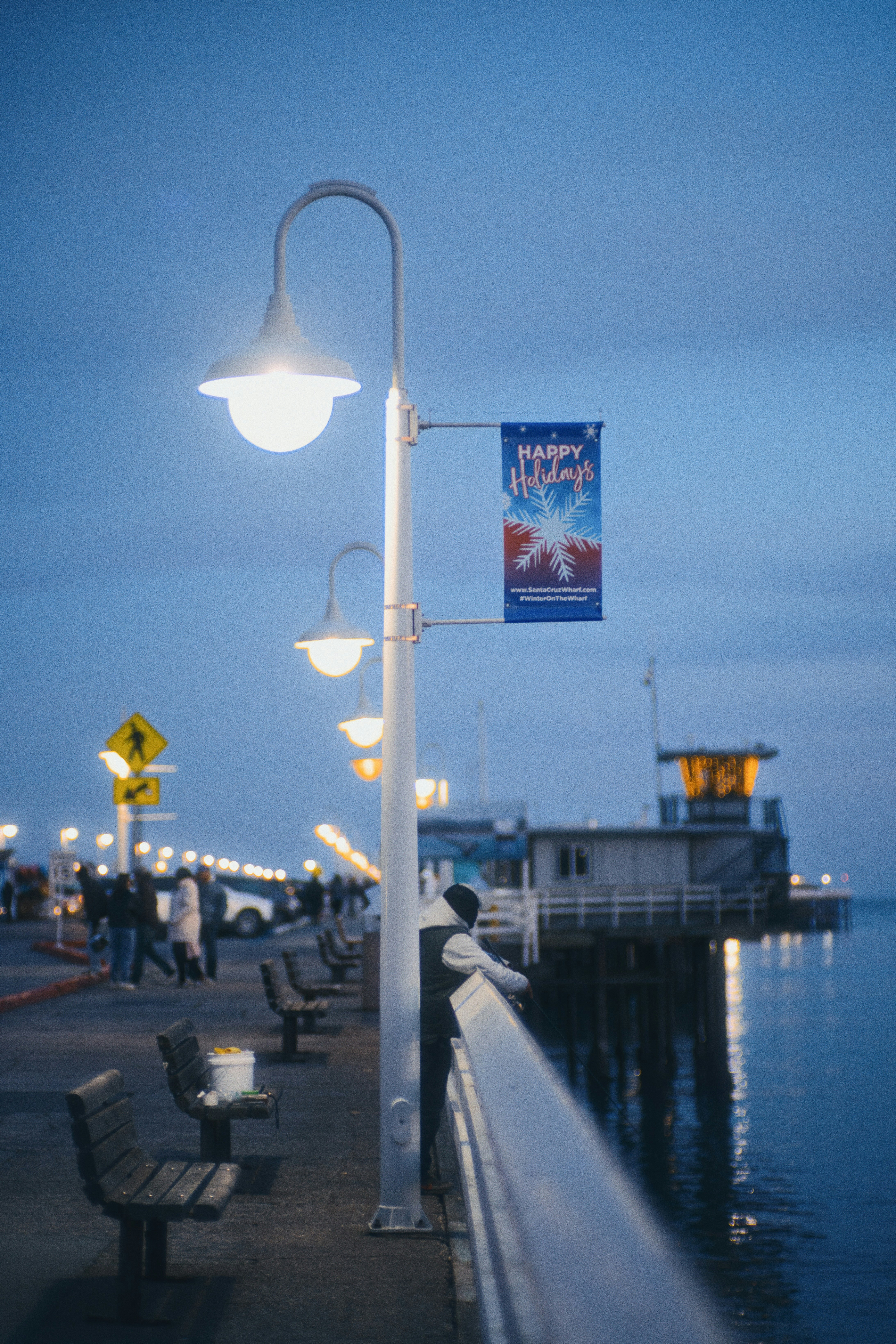 Blue Hour Promenade: Lanterns Along a Holiday Bannered Pier
