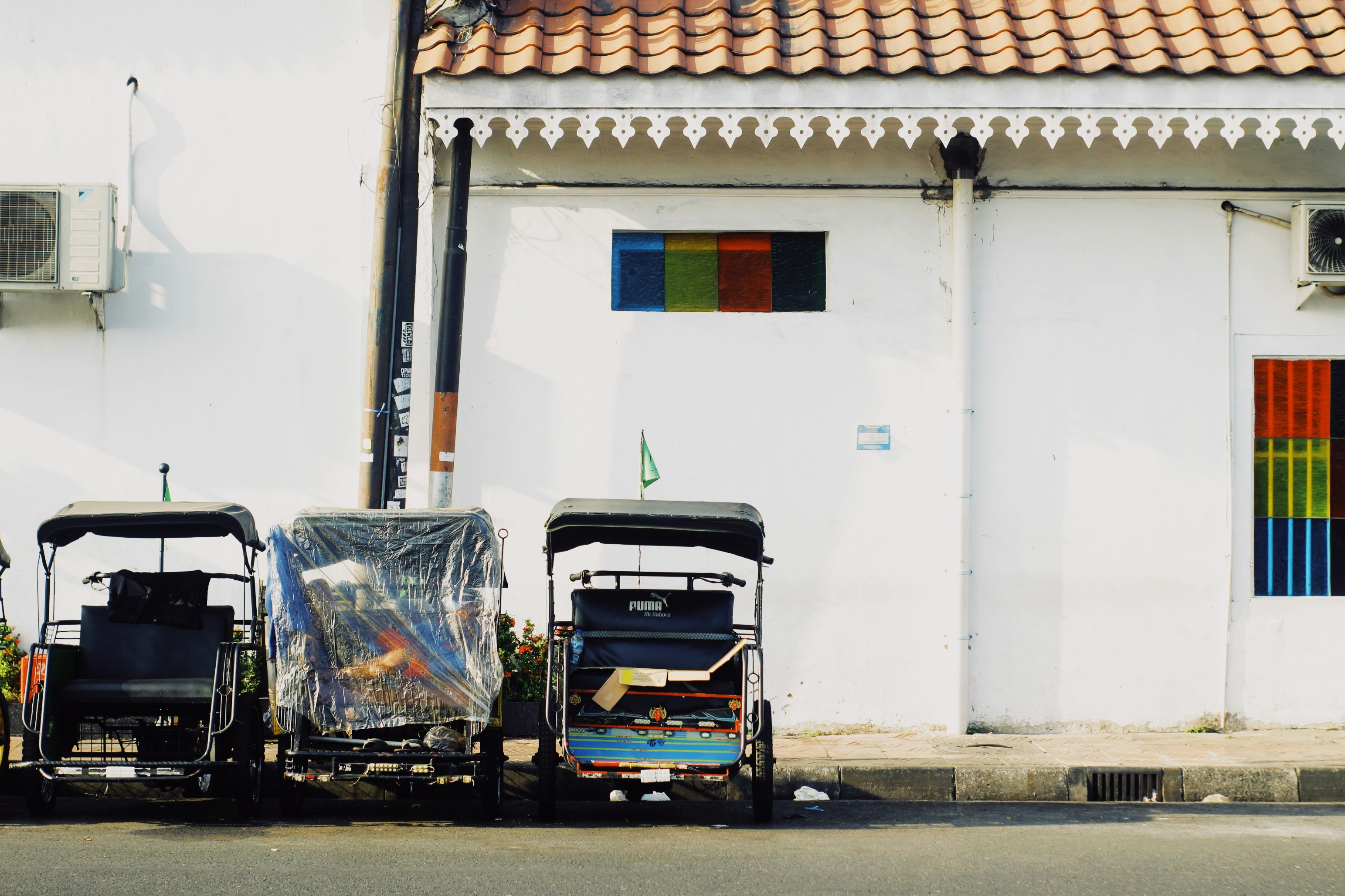 Plastic-Wrapped Cargo and Tuk-Tuks by a Color-Block Wall