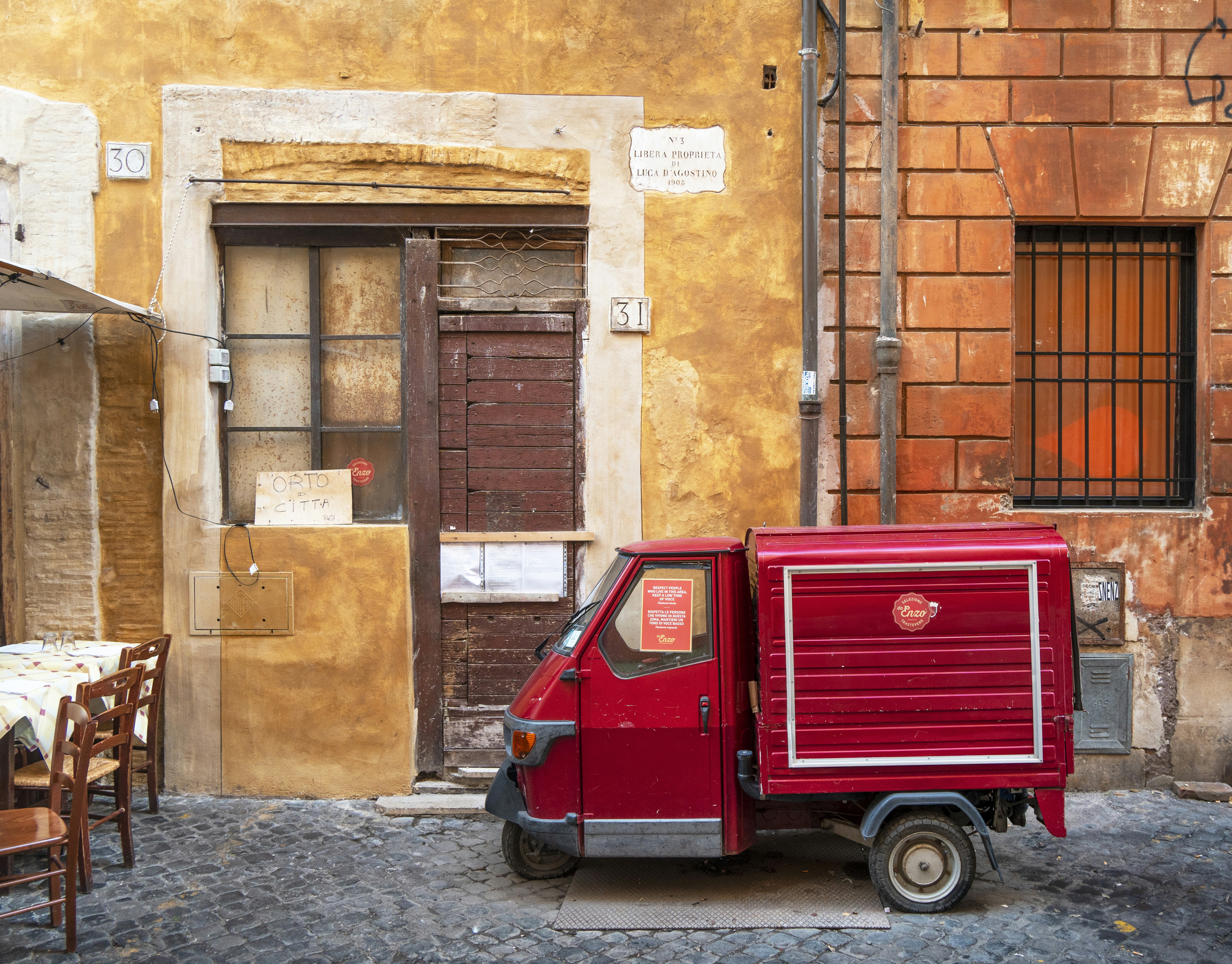Red Piaggio Ape in a Sunlit Cobblestone Alley Between Ochre Facades
