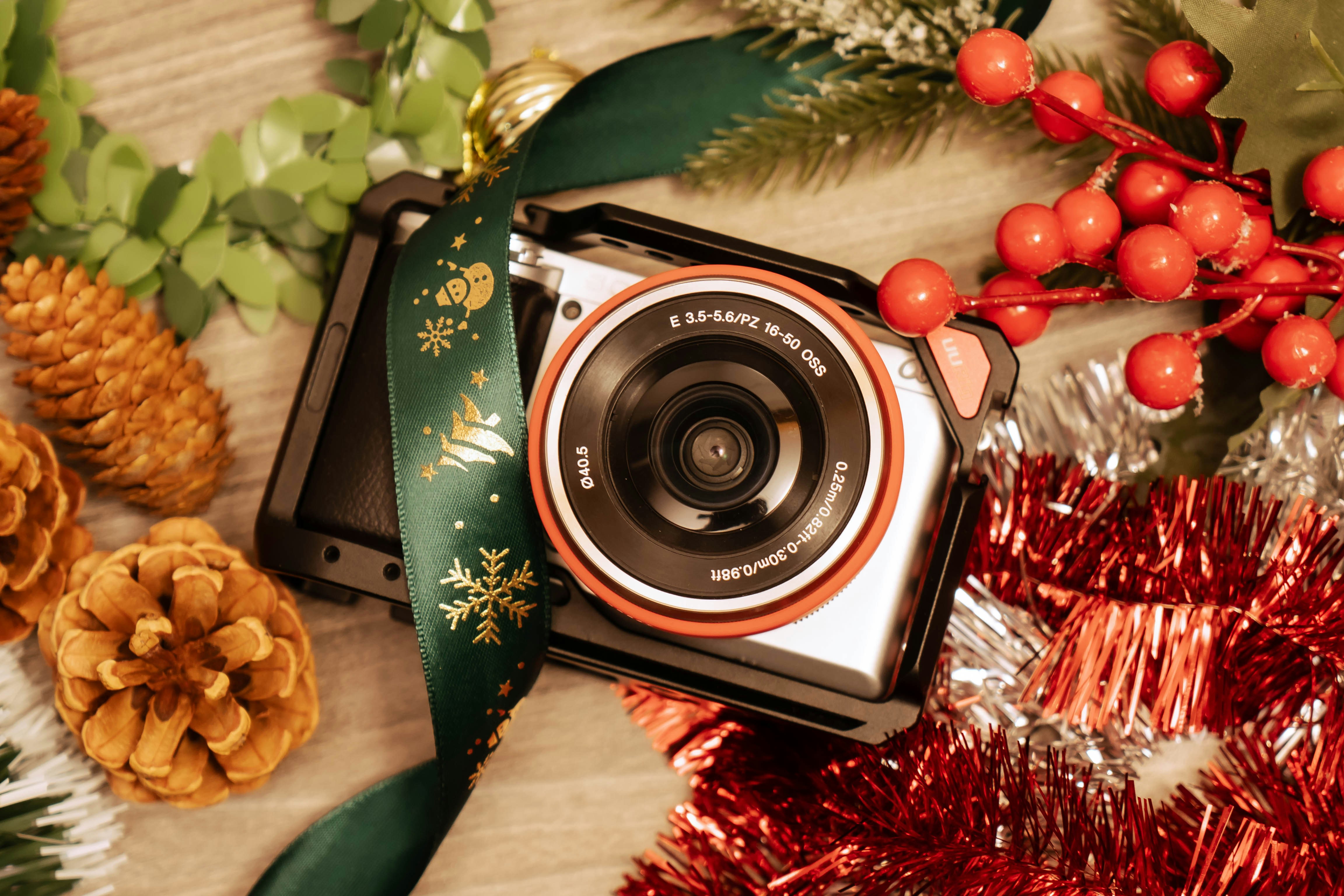 Under the Christmas Glow: A Compact Camera Cradled by Pine Cones and Tinsel