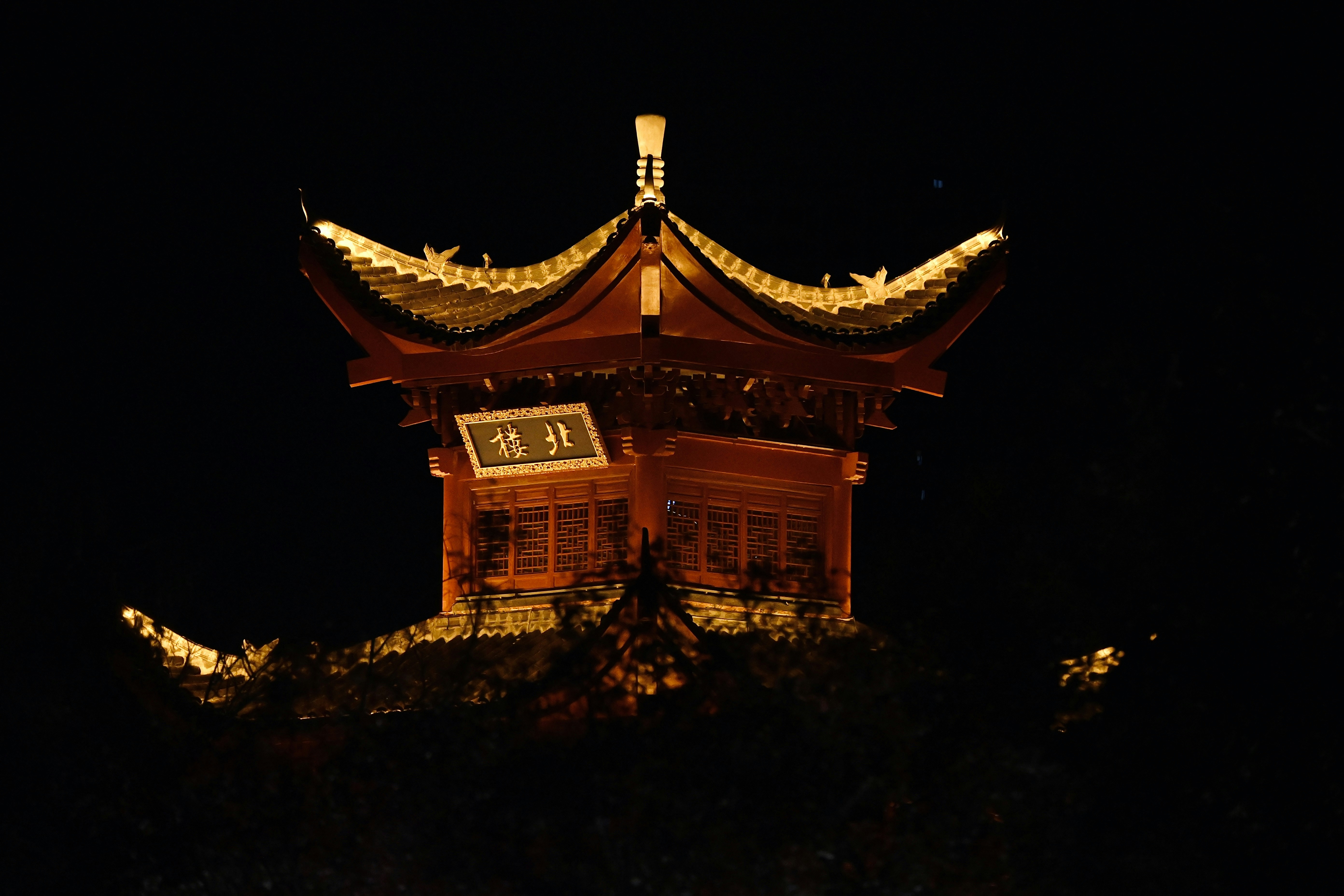 Traditional pagoda with ornate roof details lit against a dark backdrop.