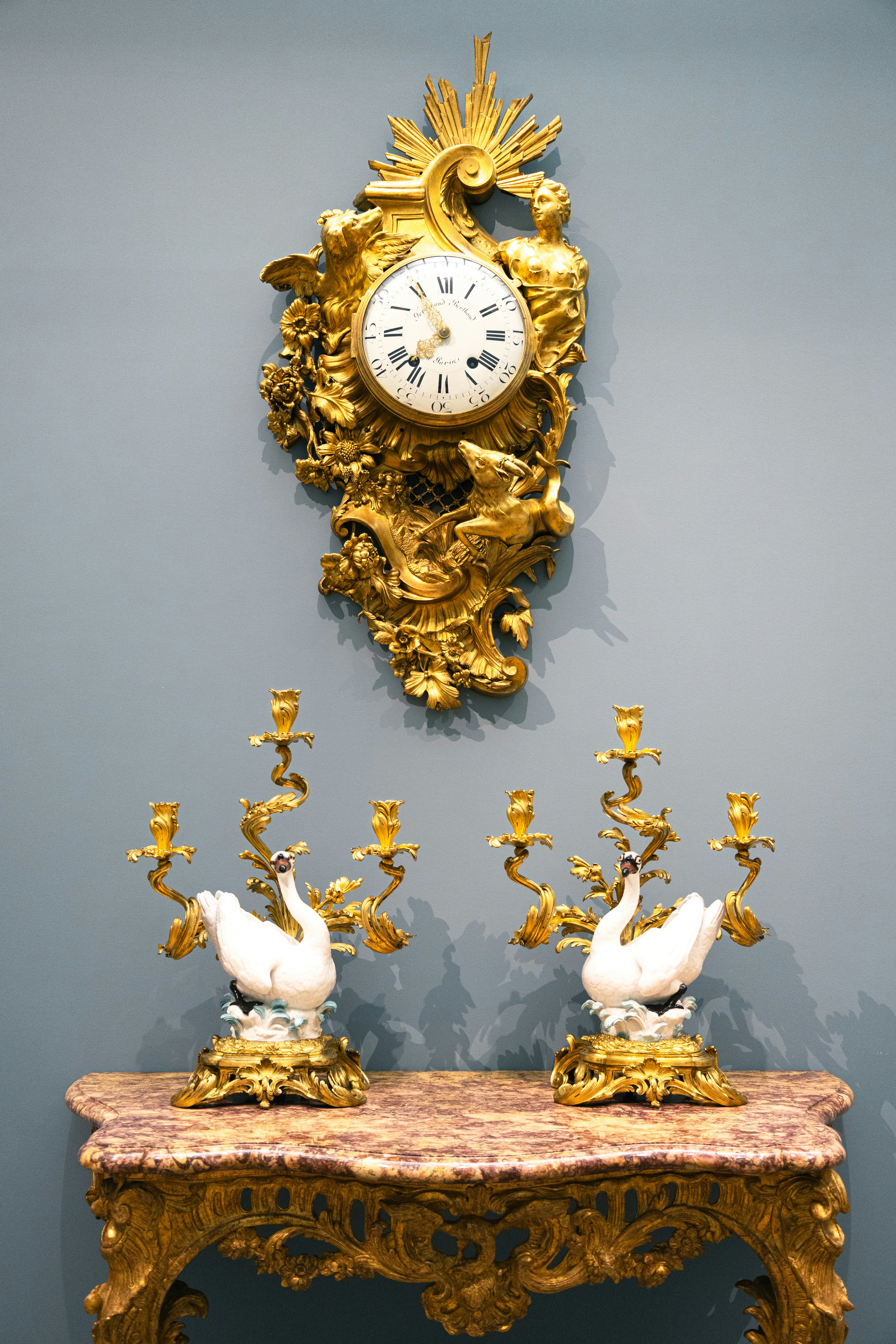 Ornate Timekeepers: A Golden Clock Surrounded by Swan Candlesticks