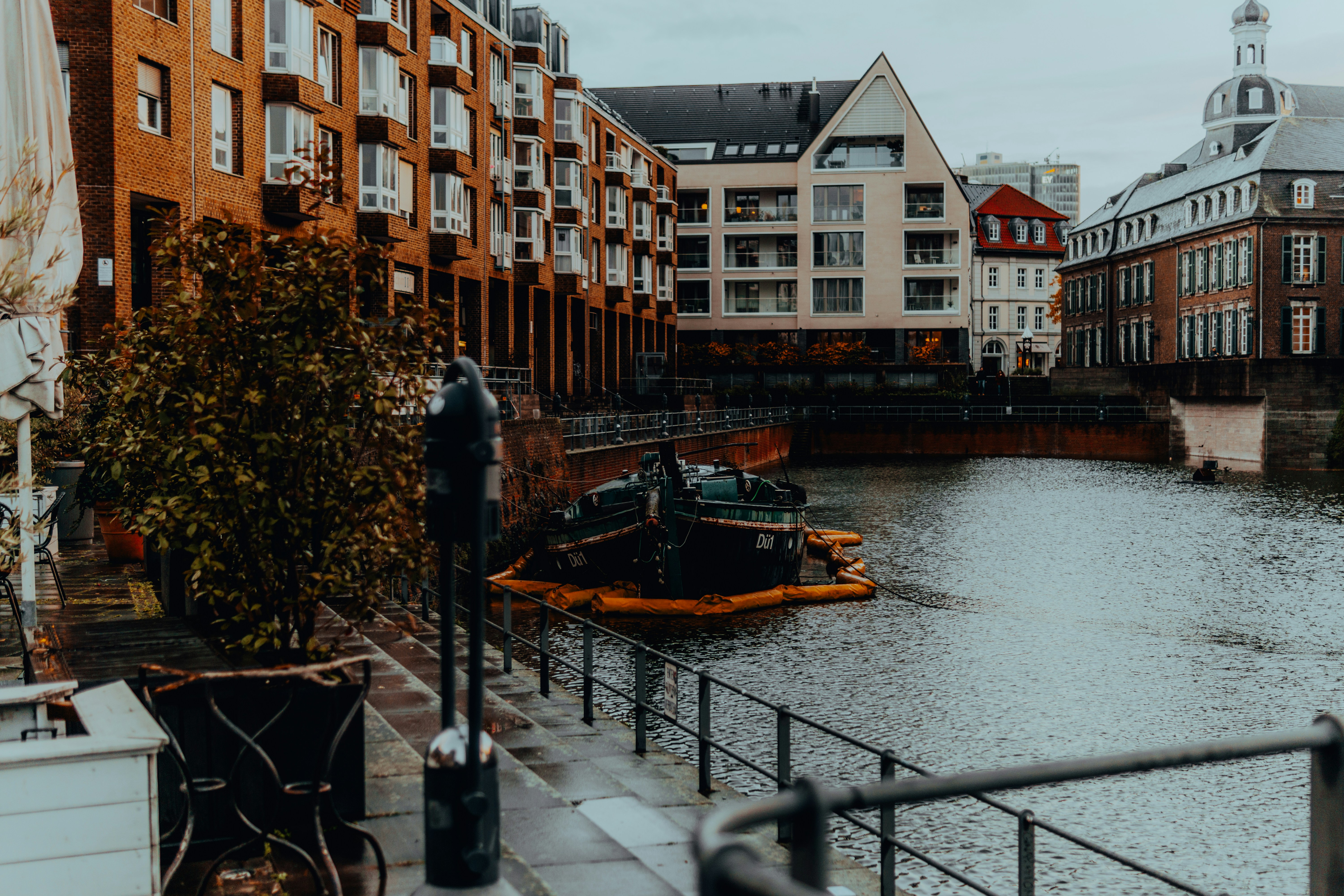 A boat floating down a river next to tall buildings photo – Free Water ...