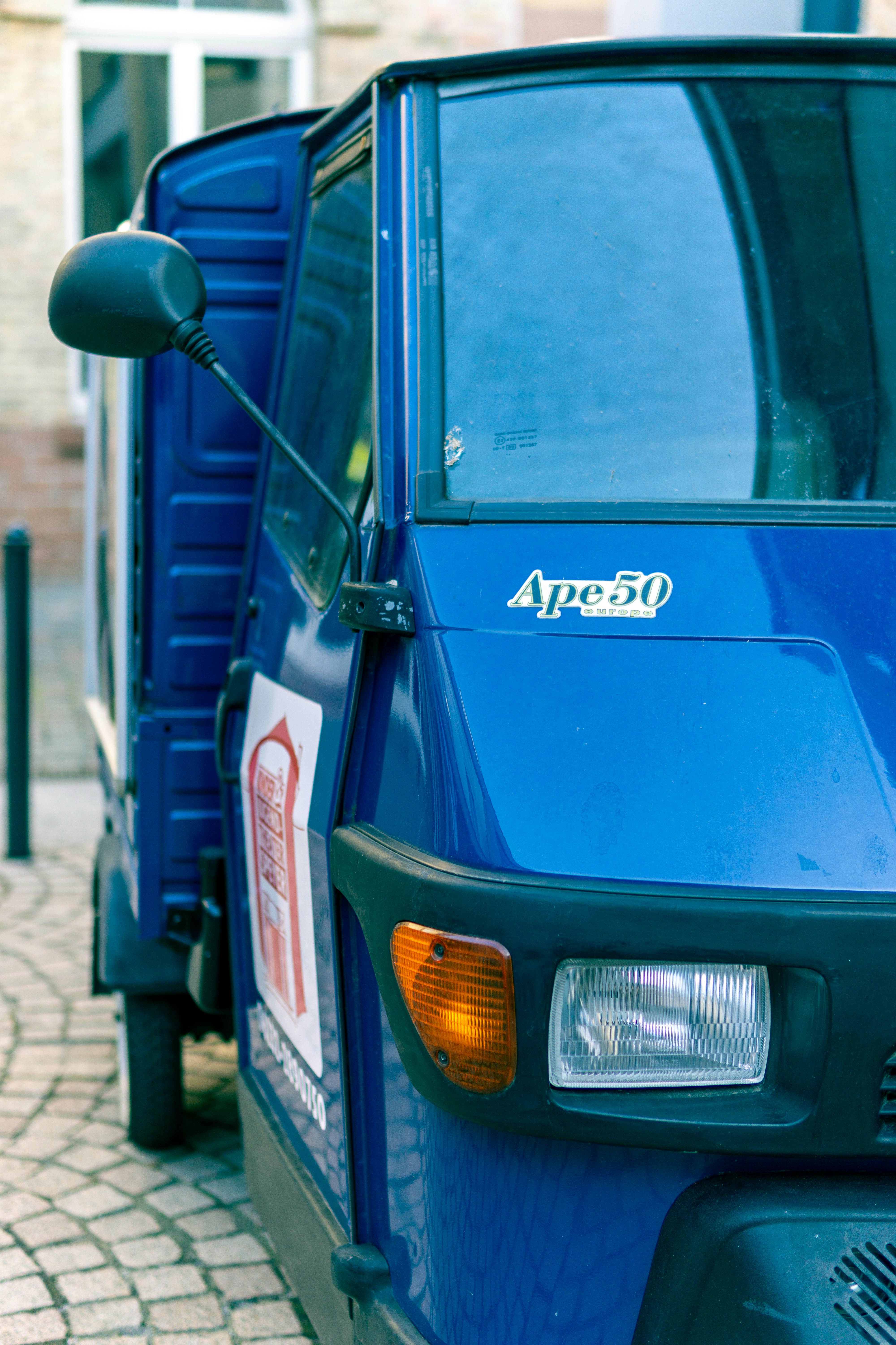 Ape 50 in Azure: Open-Door Delivery on Cobblestone Street