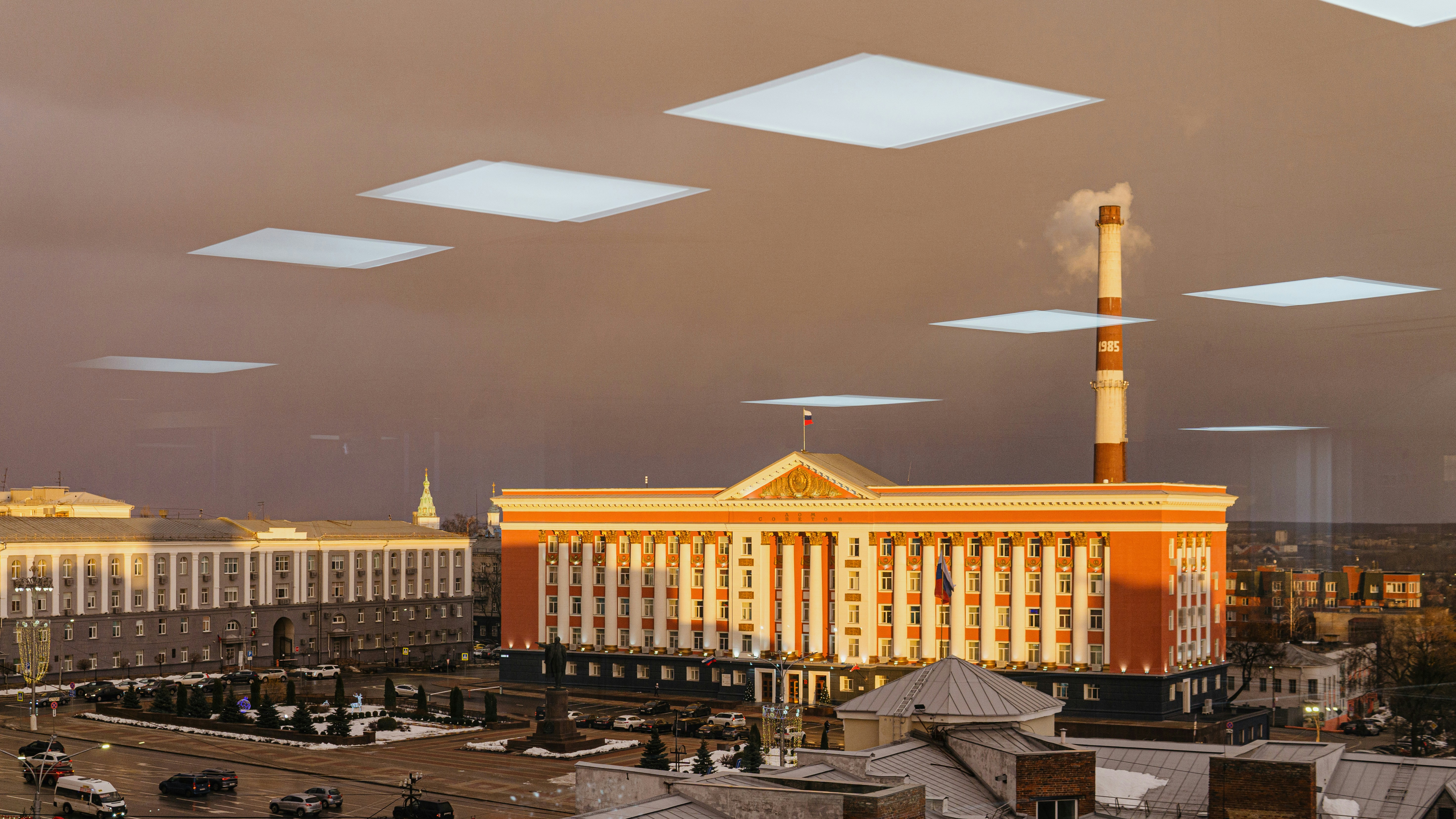 Crimson Facade at Dusk: An Orange Administrative Hall Framed by a Smokestack
