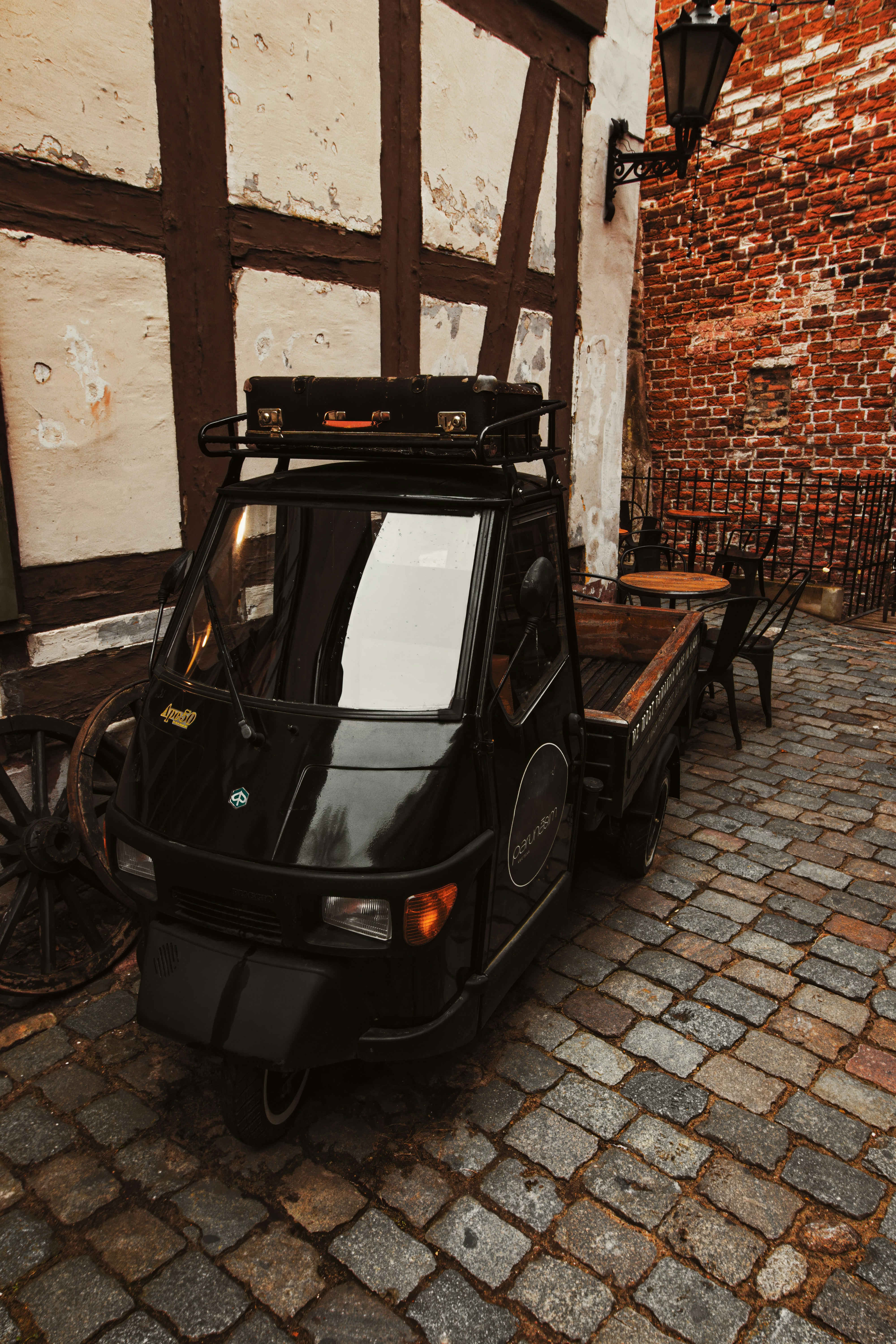 Mini Hauler on Cobblestones: A Black Cargo Trike Beside Timber-Framed Facades