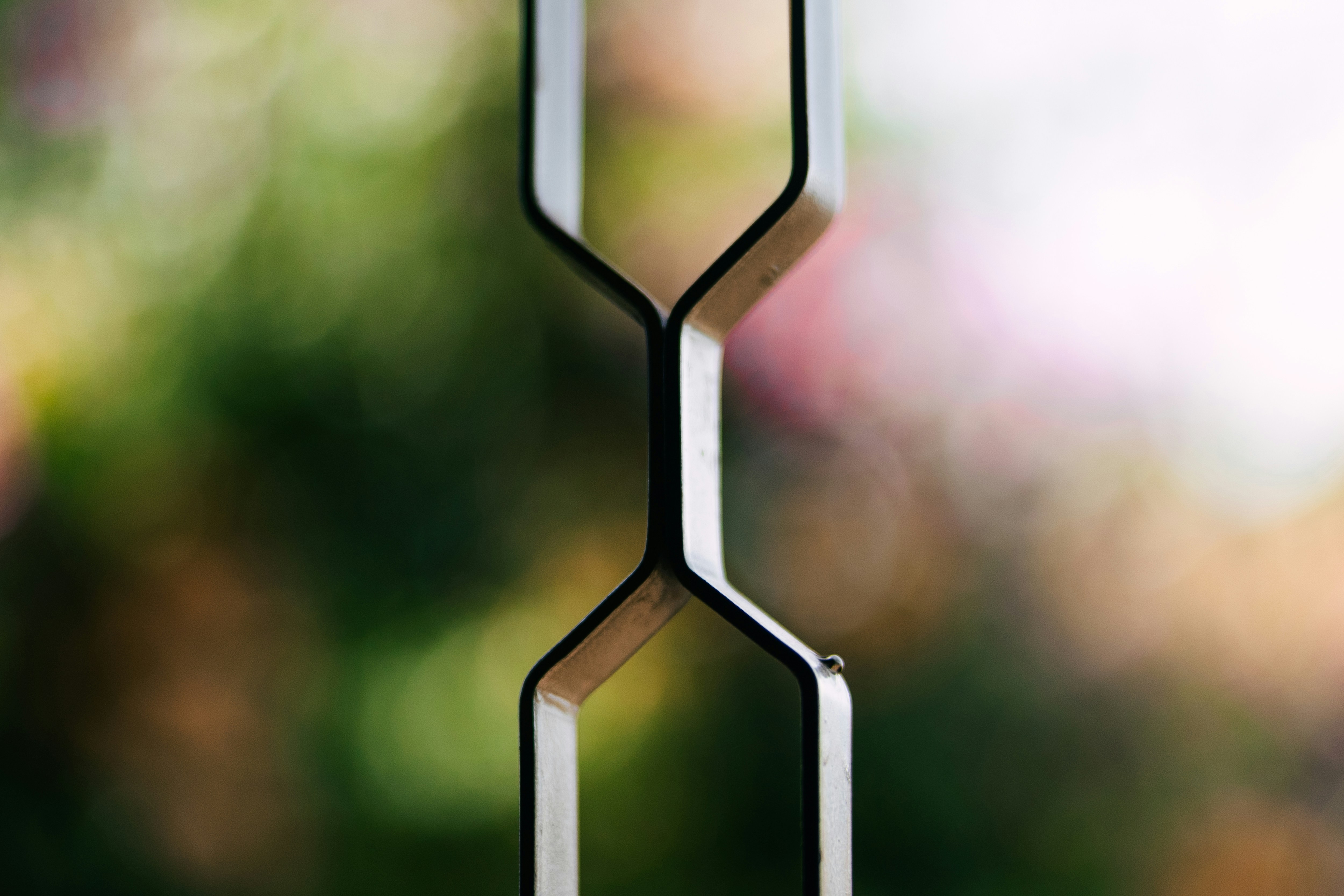 Hourglass Geometry: Steel Lattice Framed by Garden Blur