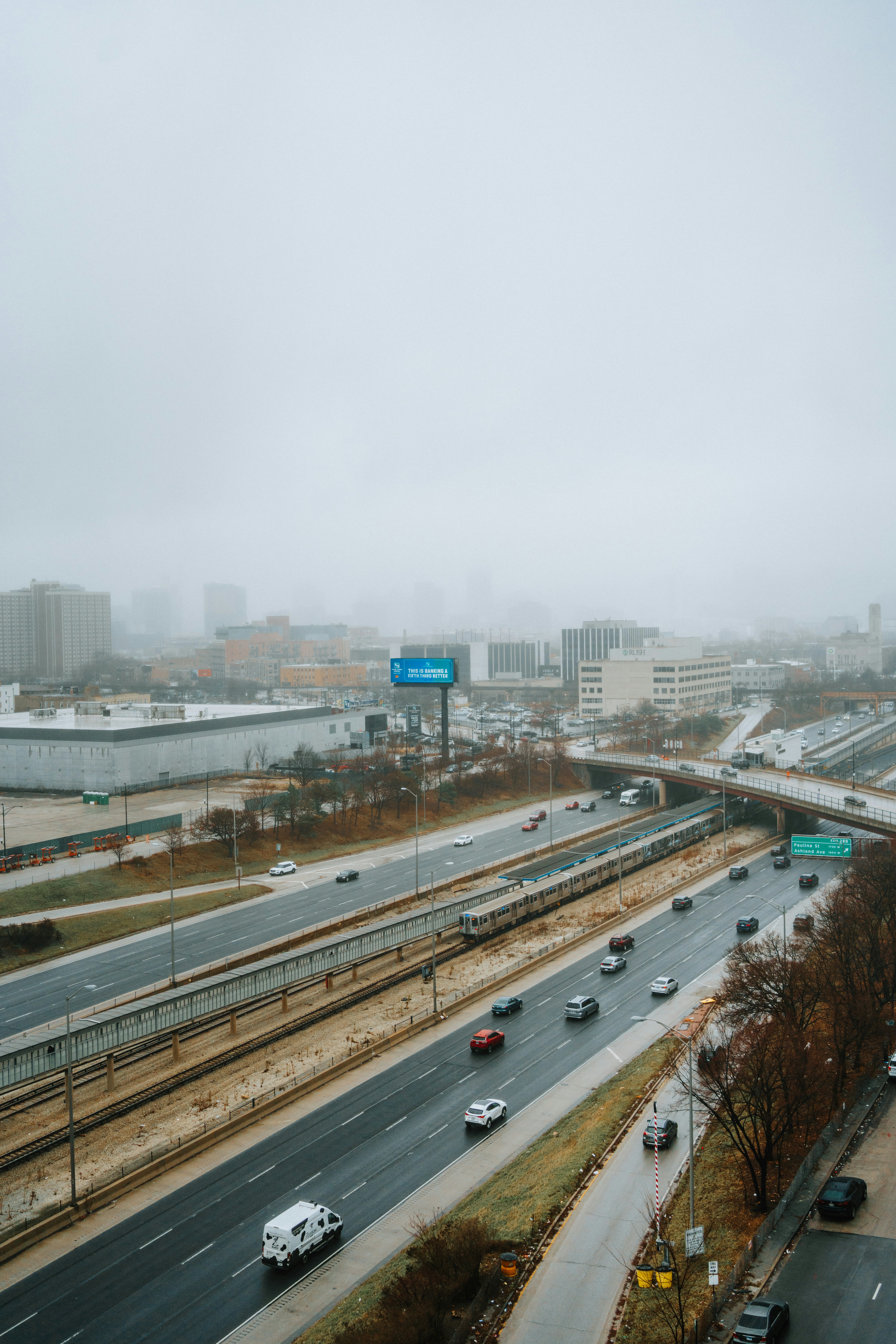Fog-Wrapped Freeways Thread Through a Quiet City Toward a Distant Skyline