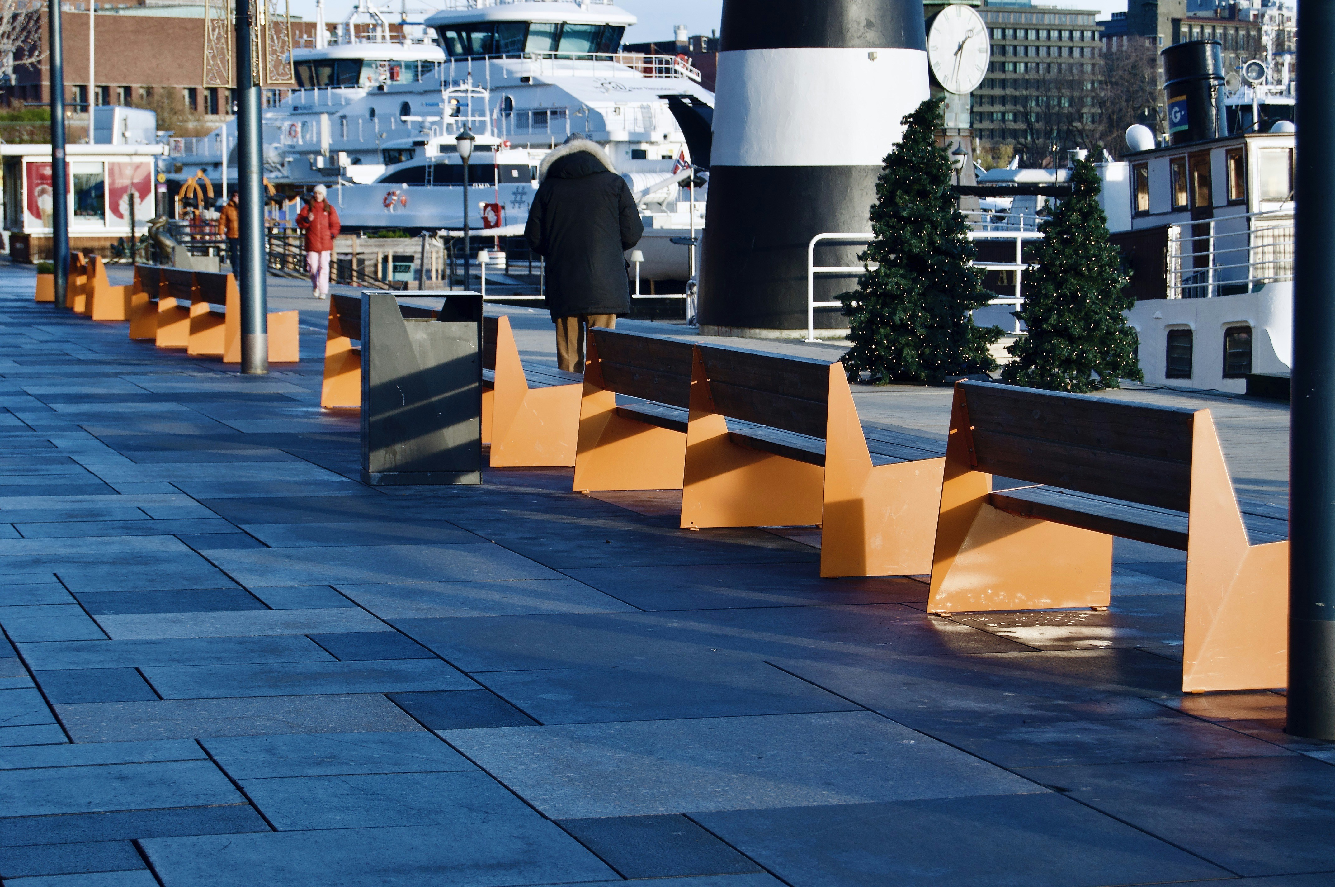 Harbor Walk: Orange Angular Benches Align a Quiet Waterfront Path