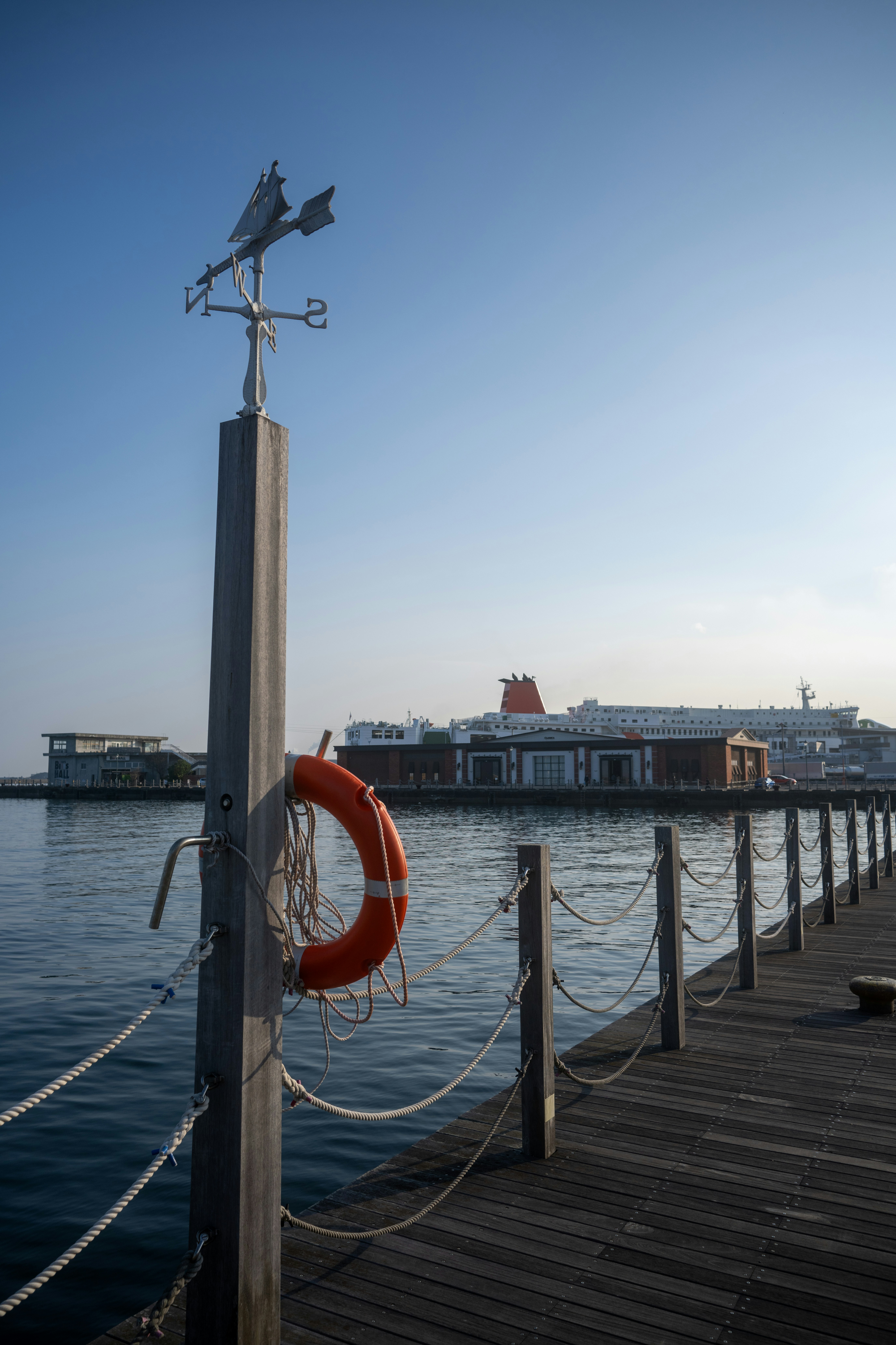 A dock with a life preserver and a ship in the background photo – Free ...