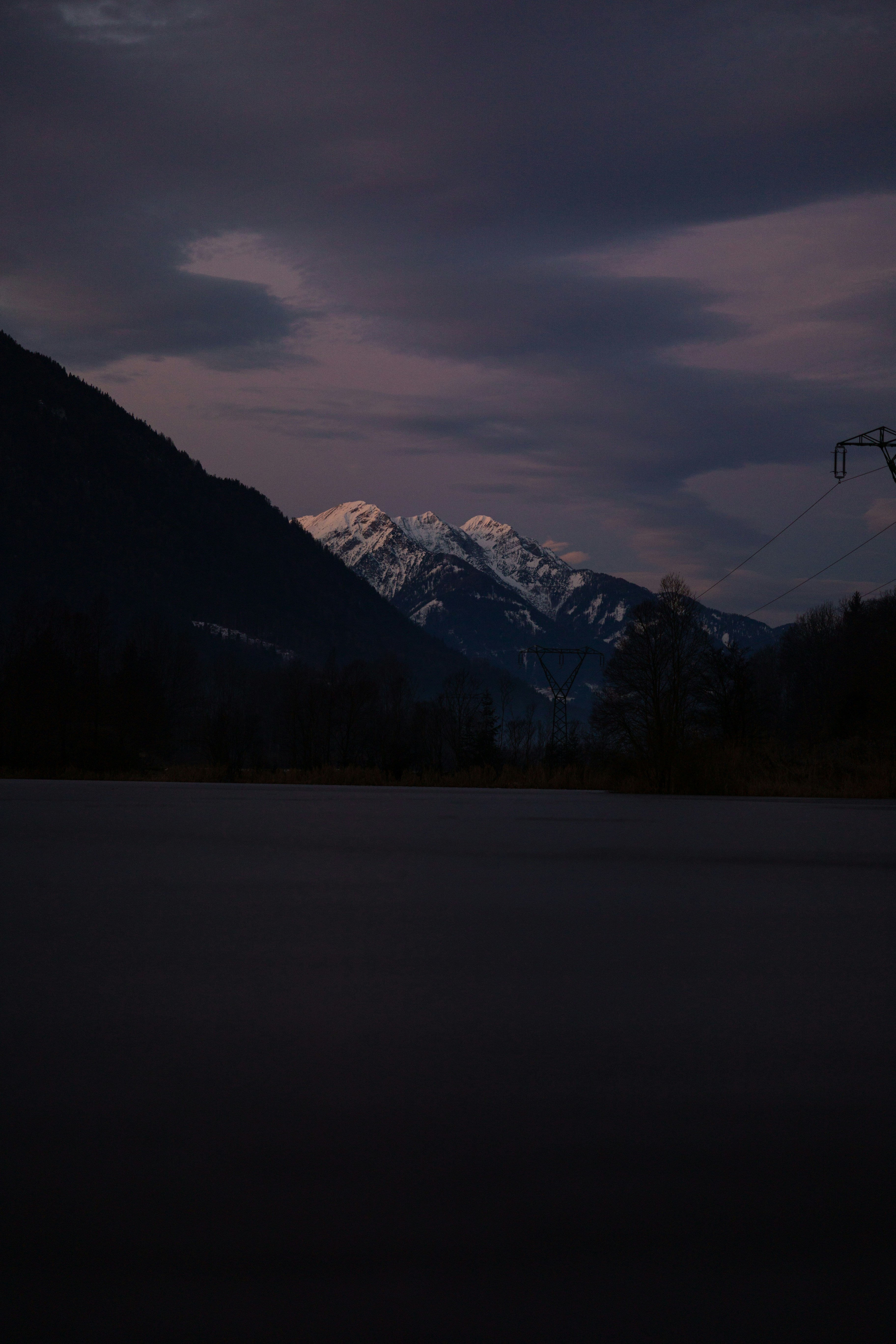 Snow-capped Peaks Emerging at Dusk Beyond a Quiet Valley